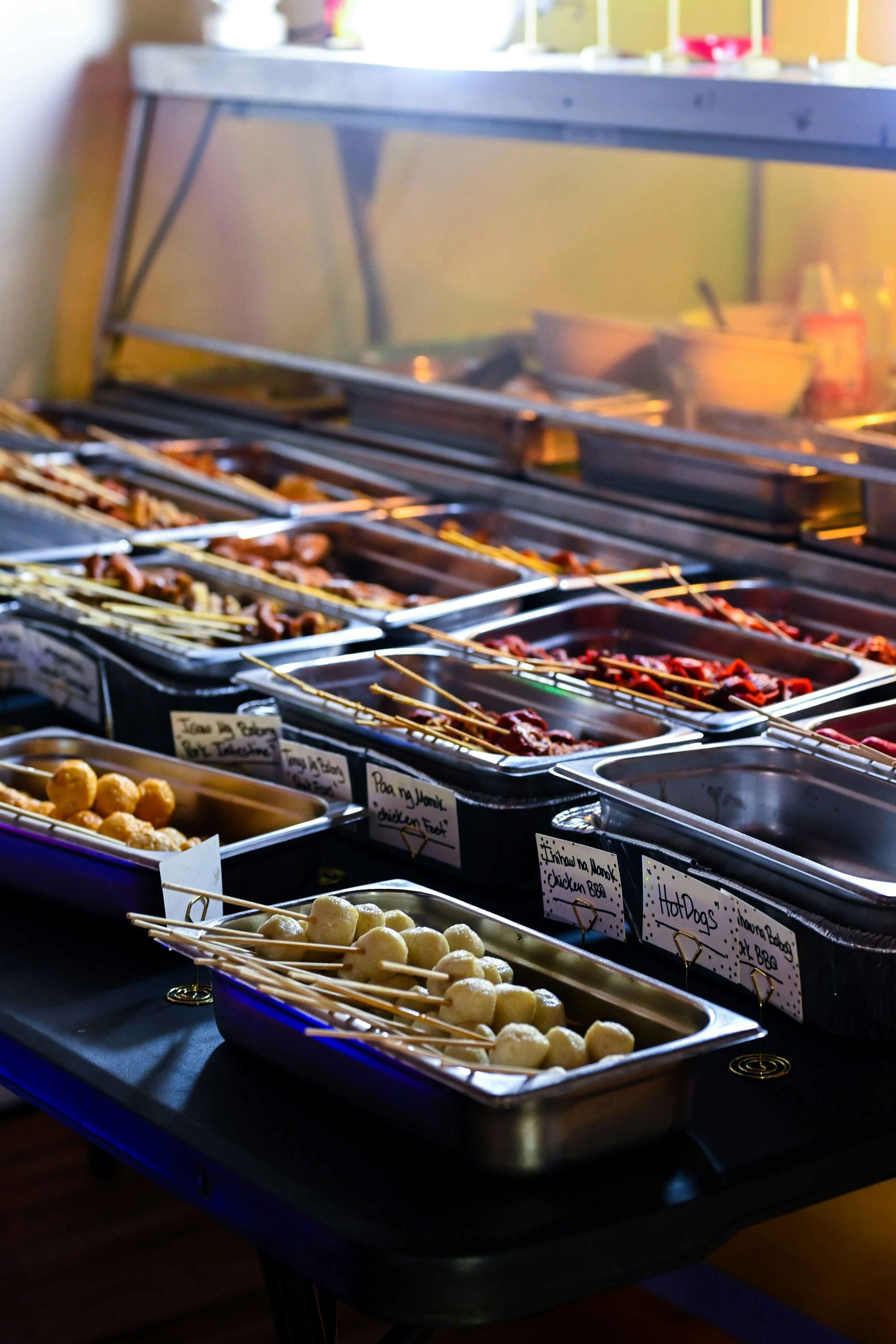 Skewered Delights Under Amber Glow at a Busy Food Counter