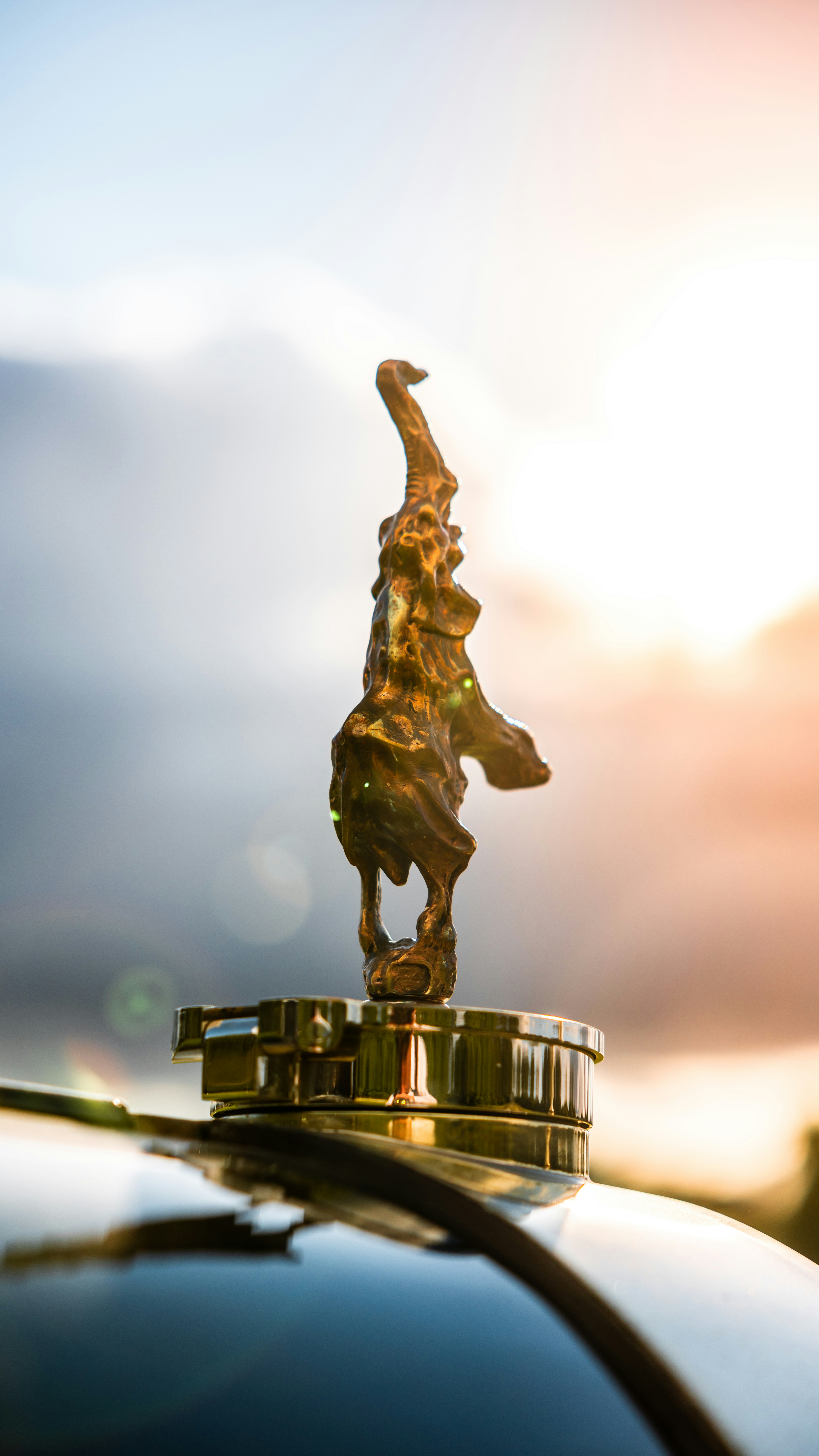A bronze hood ornament is seen against a sunset. photo – Free ...
