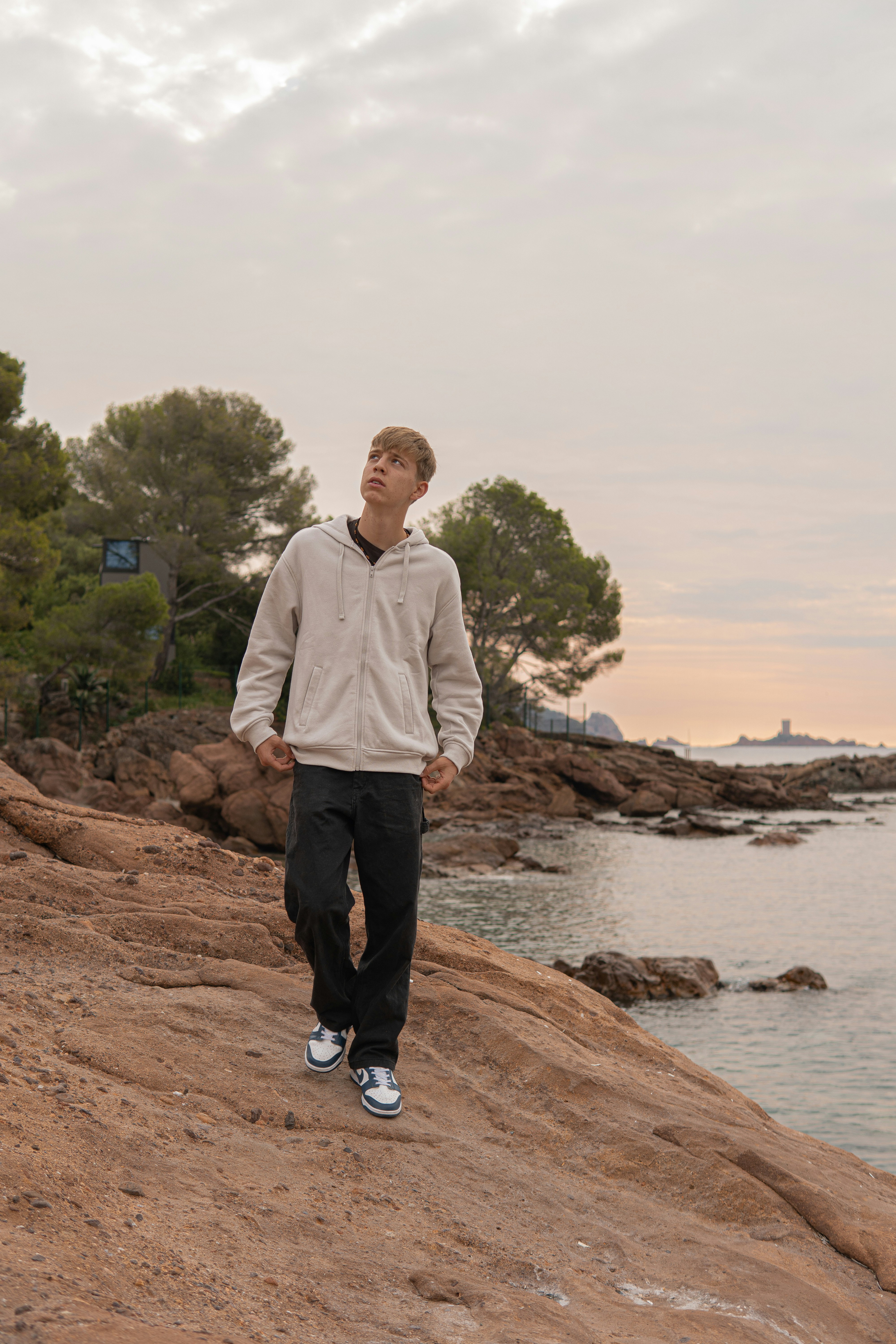 Hooded Walk at Dusk Along Sun-Warmed Coastal Rocks