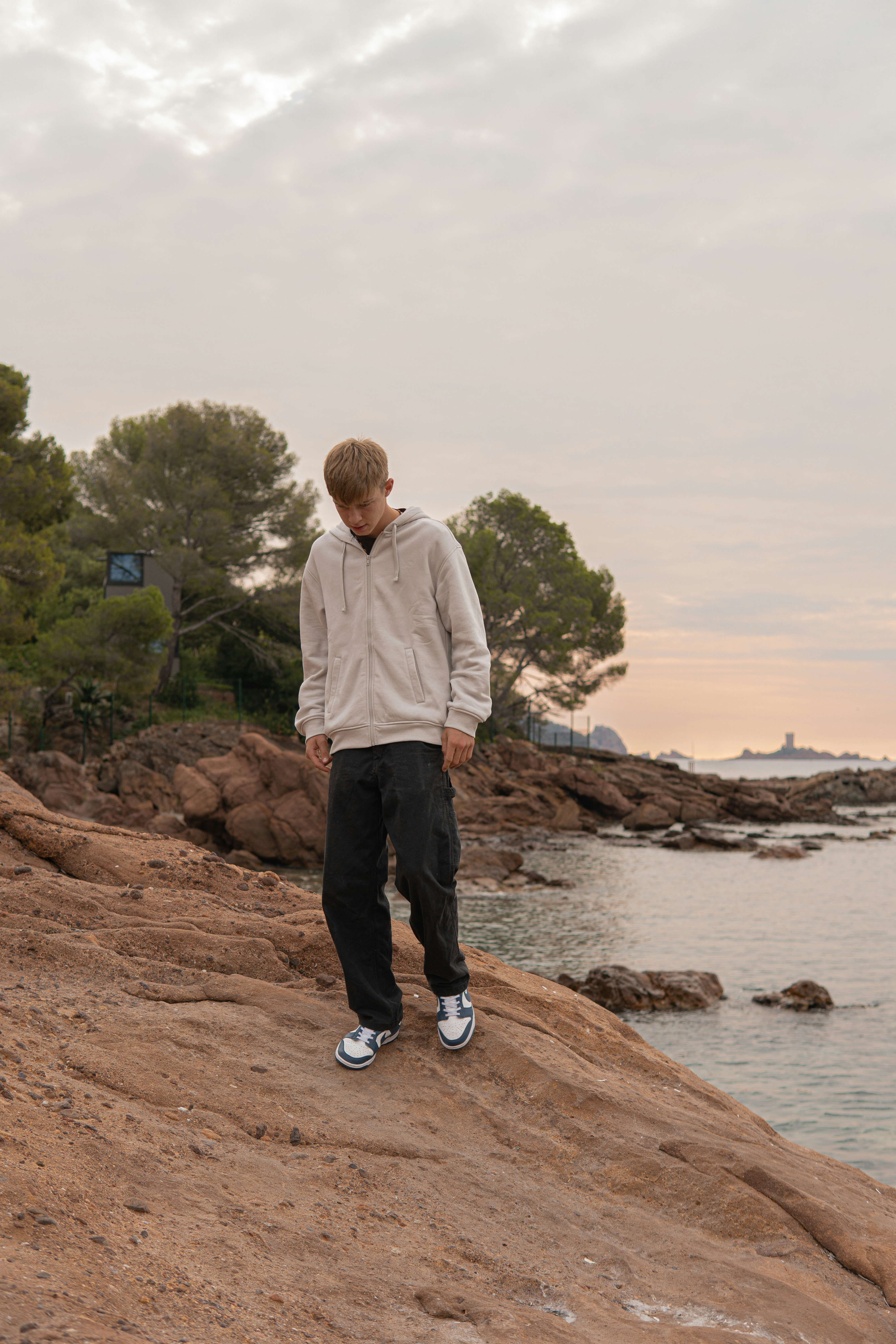Dusk on the Ragged Shore: A lone figure pauses on sun-warmed rocks