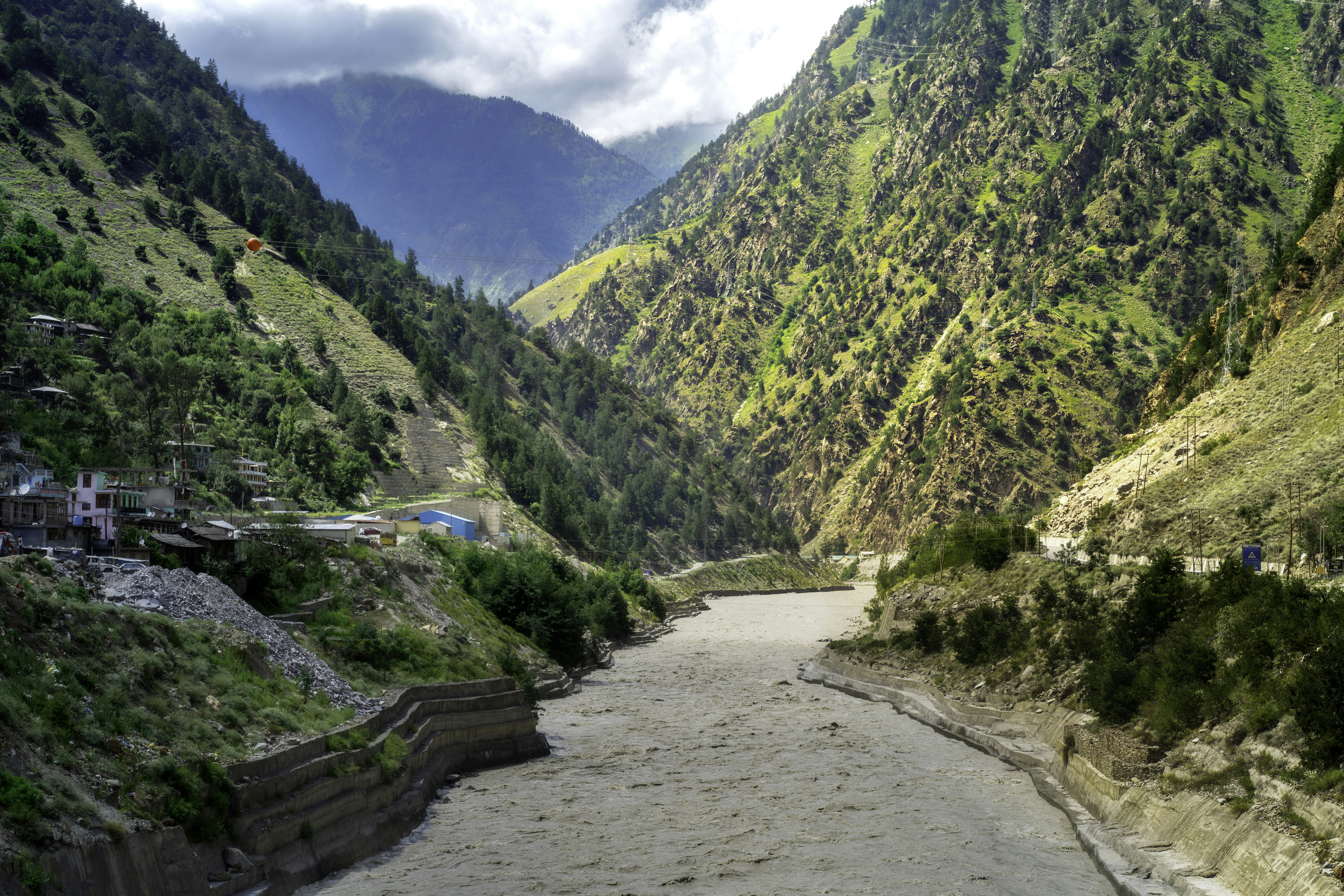 Mountain river meanders through a vibrant green valley with scattered village homes and terraced fields.