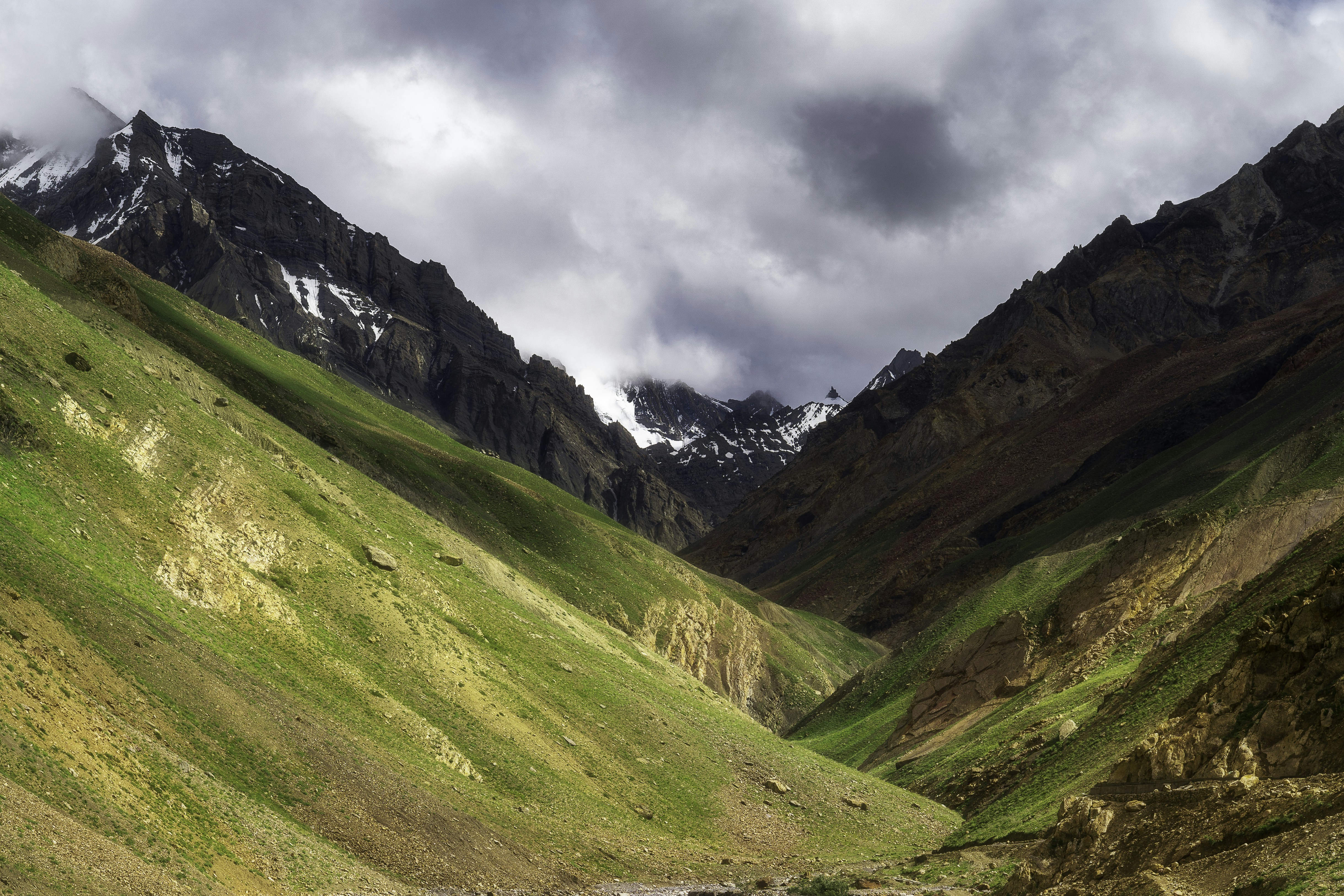 Verdant Corridor: Light Folds Through a Valley Between Rugged, Snow-tipped Peaks