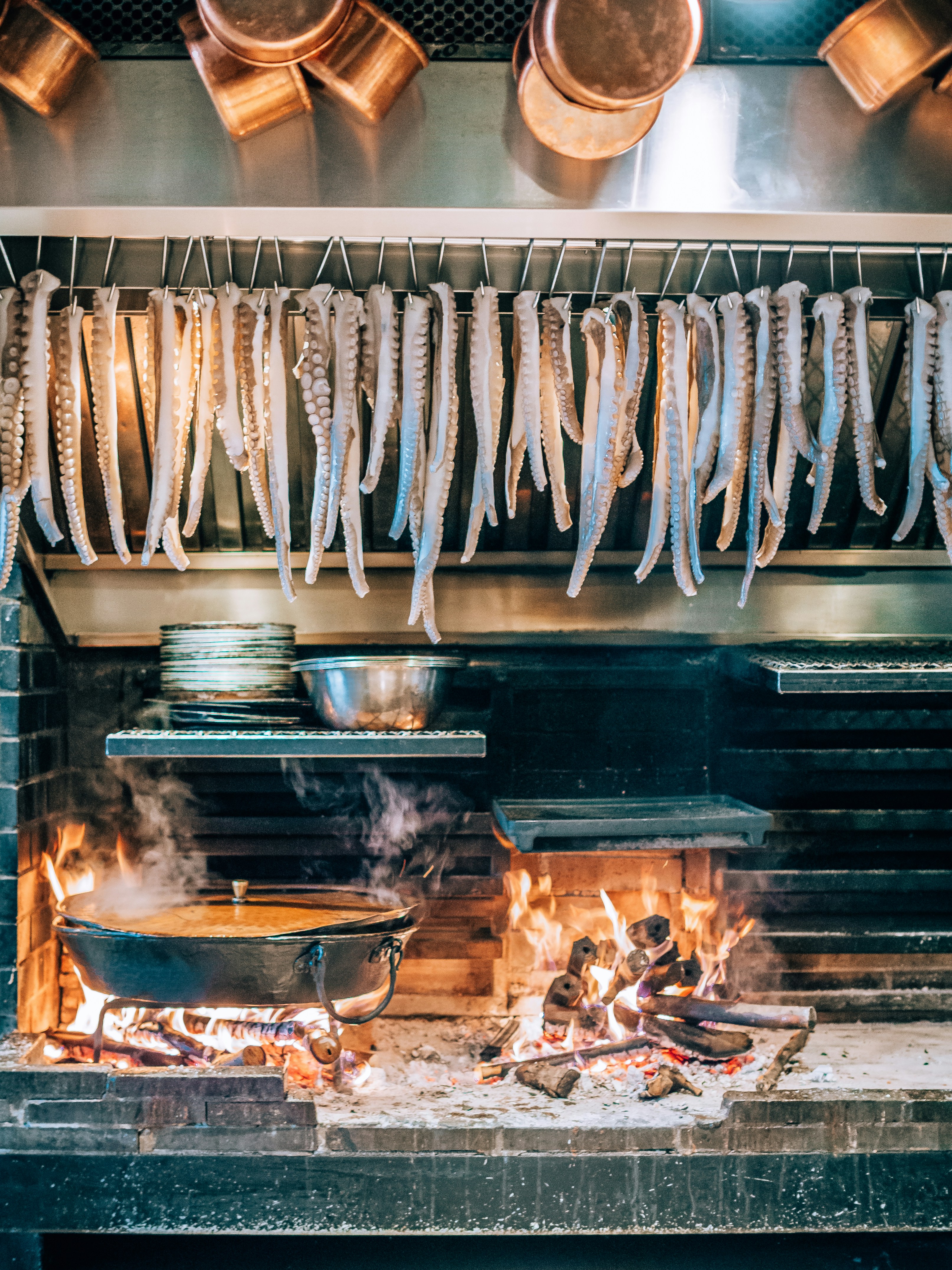 Row of Hanging Fish Over Open Flames in a Rustic Kitchen