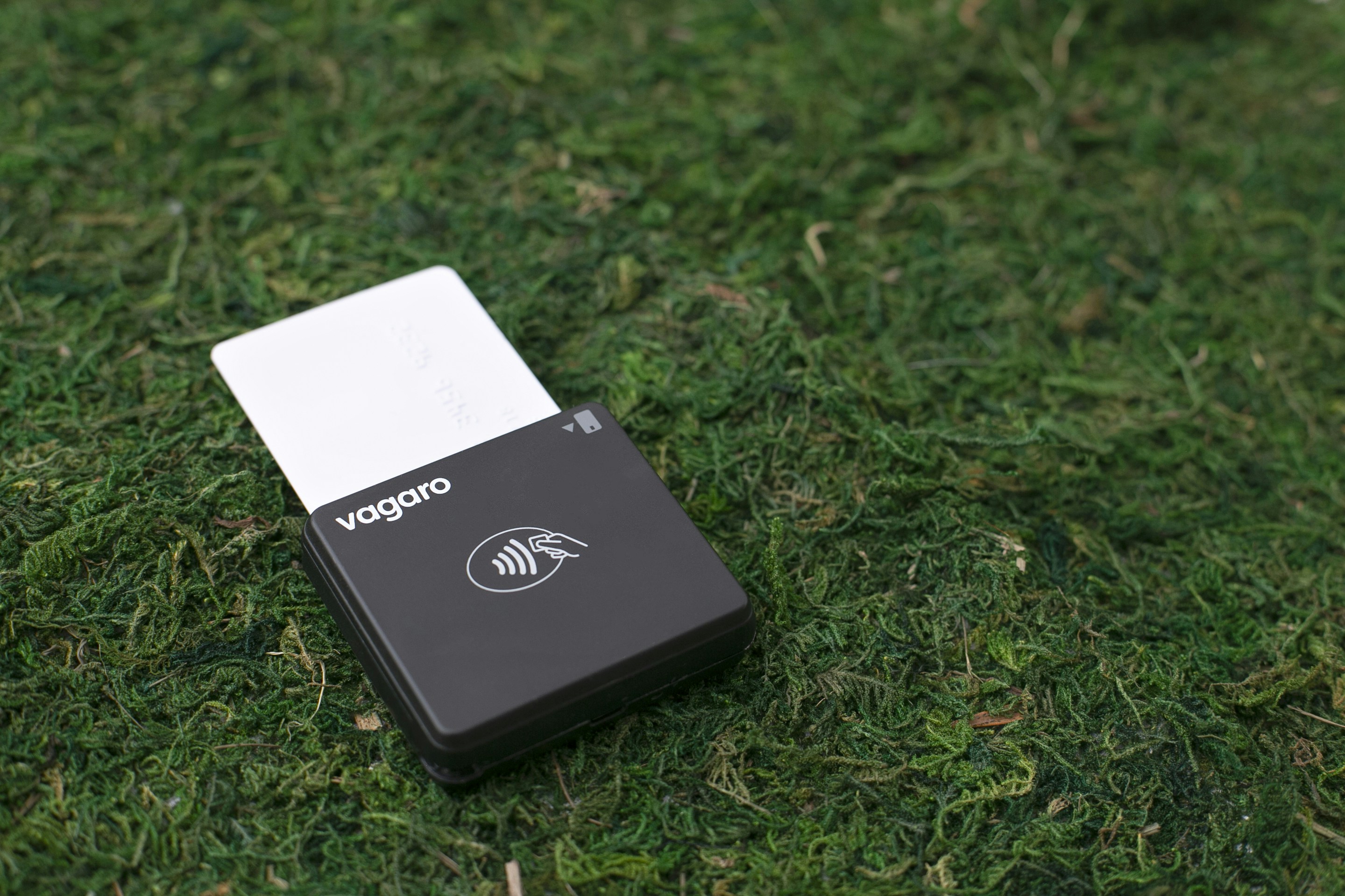 Vagaro card reader resting on a bed of lush green moss, symbolizing modern payment solutions in a natural setting.