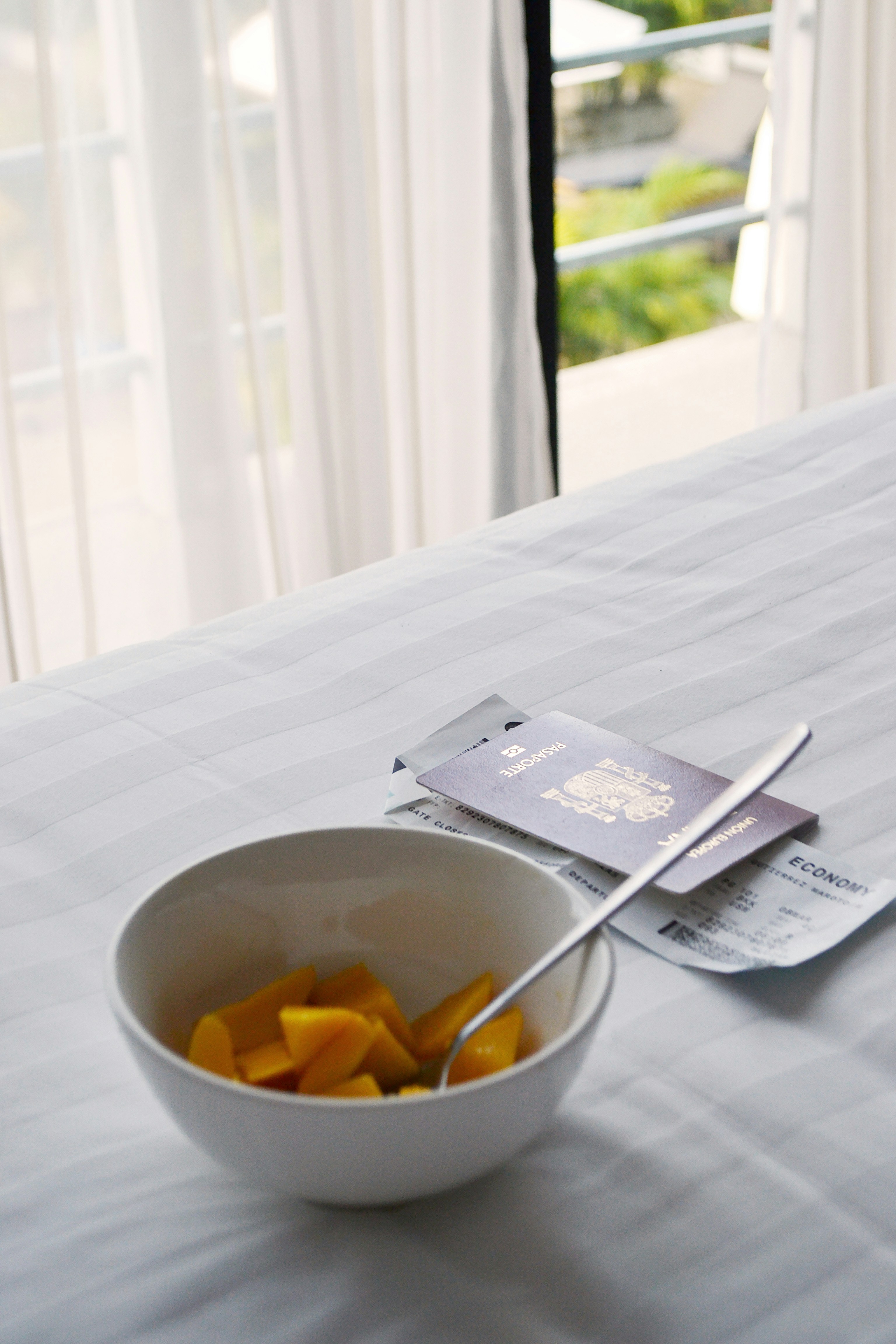 Mango bowl, passport, and plane ticket on a bed. photo – Free Food ...