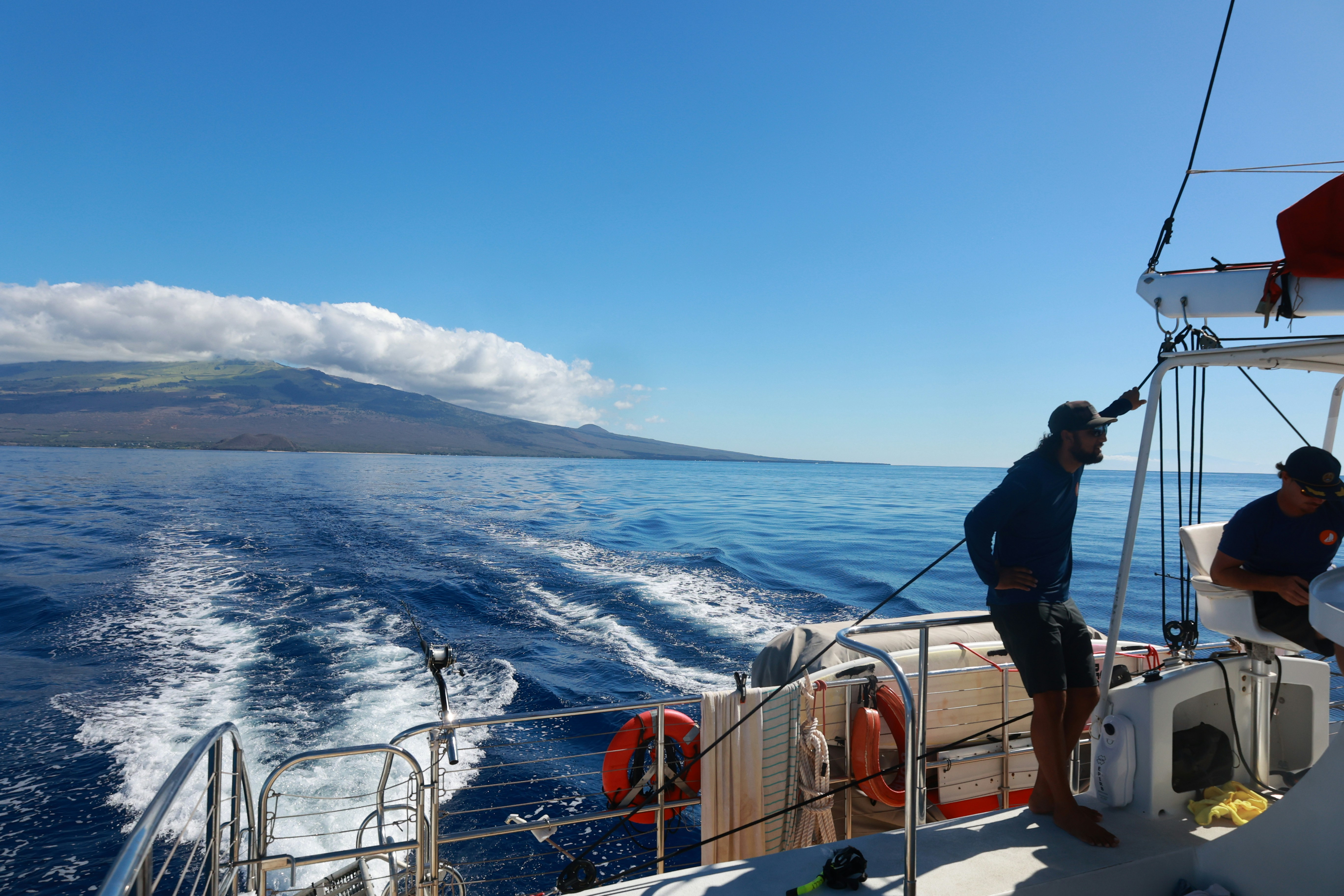 Sailboat navigates the ocean with land in the background.