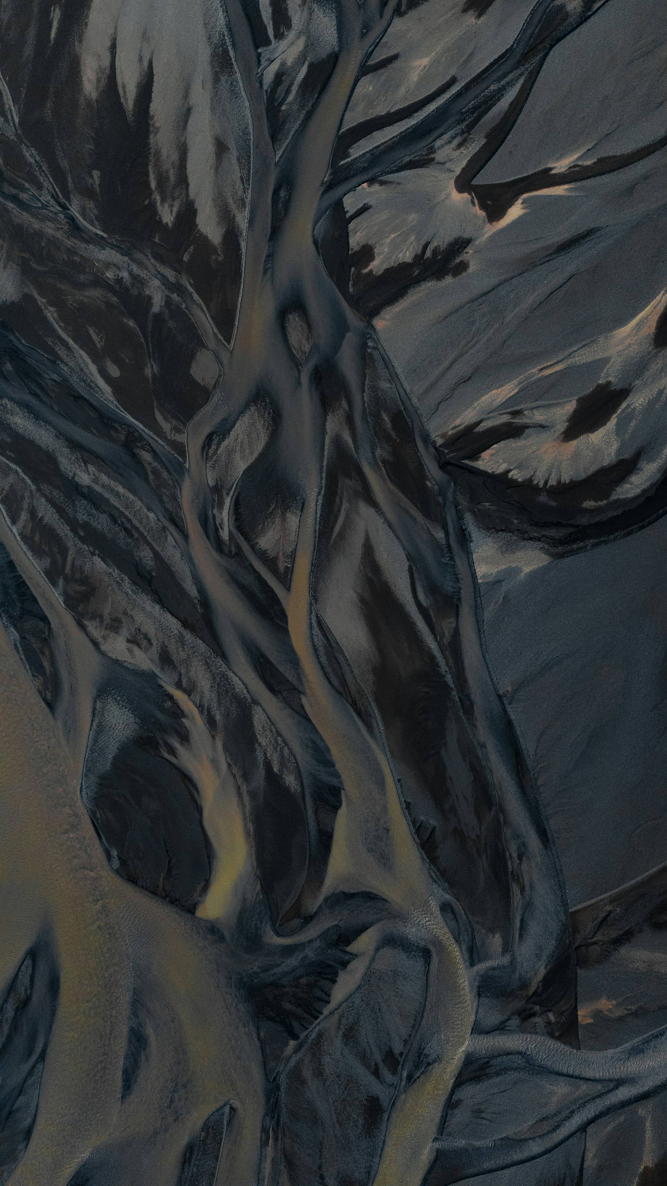 Abstract aerial view of braided glacial rivers in Iceland with intertwining dark and light streams.