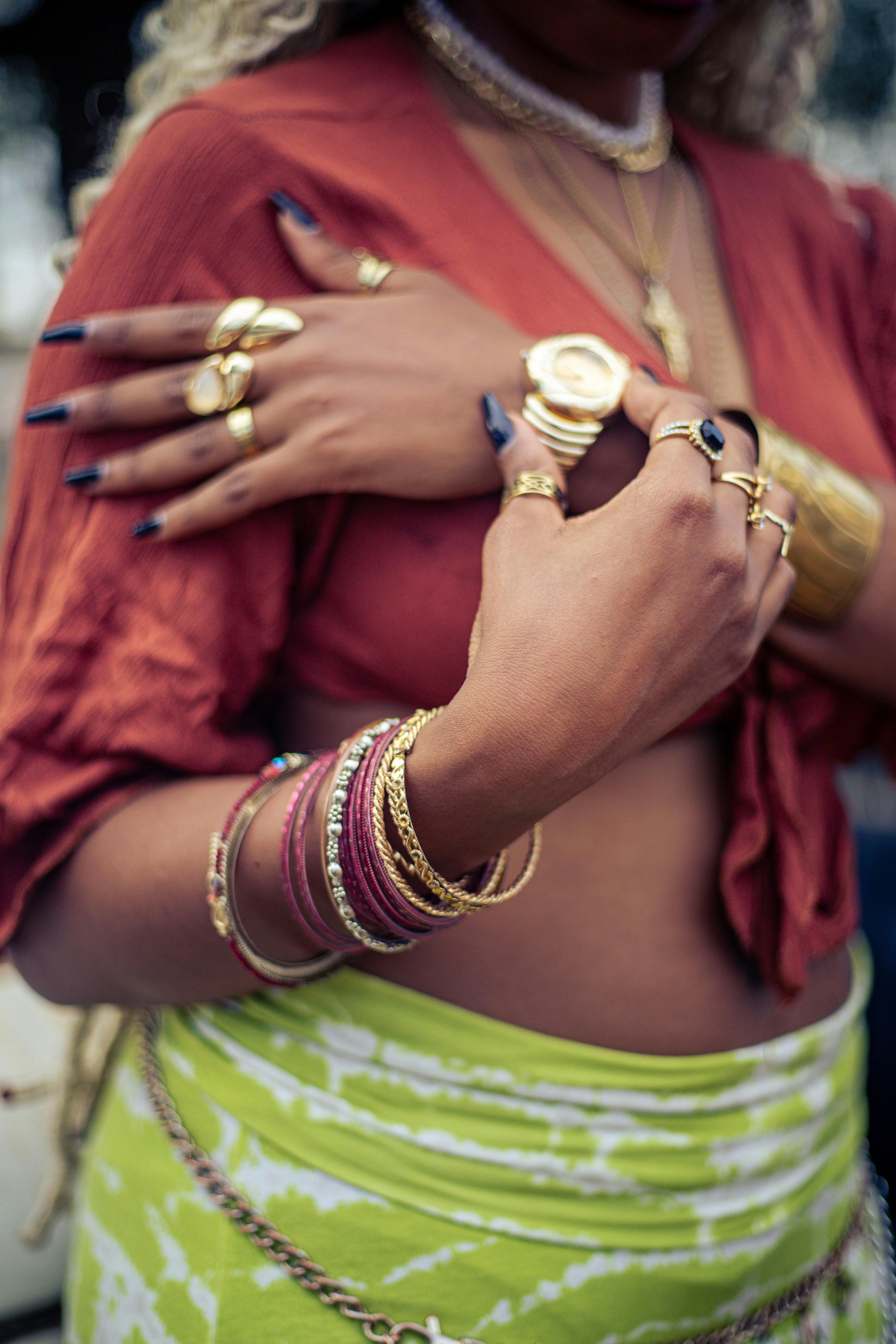 Gilded Hands, Bold Hues: A Close-Up of Jewelry Over Red Fabric and Lime Tie-Dye
