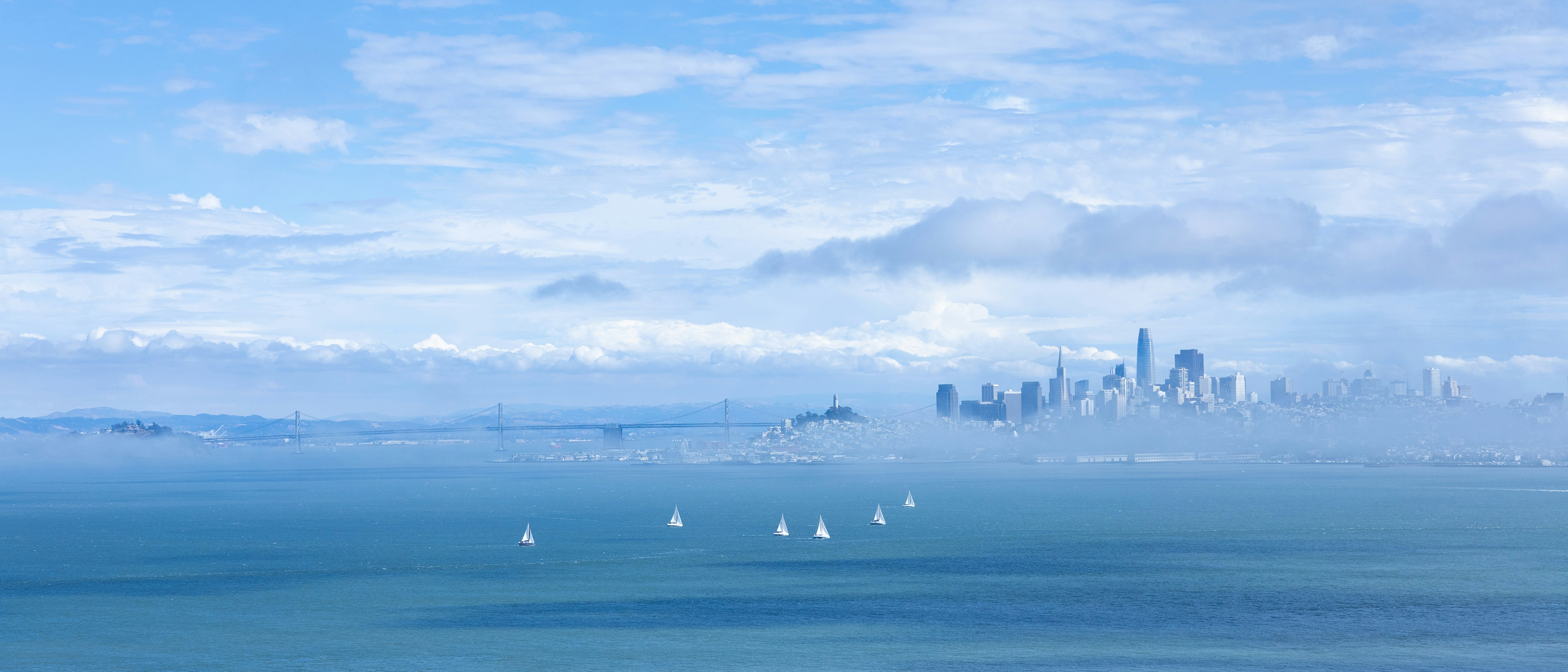 Fleet of White Sails Drifts Across a Cerulean Bay Toward a Faint Skyline