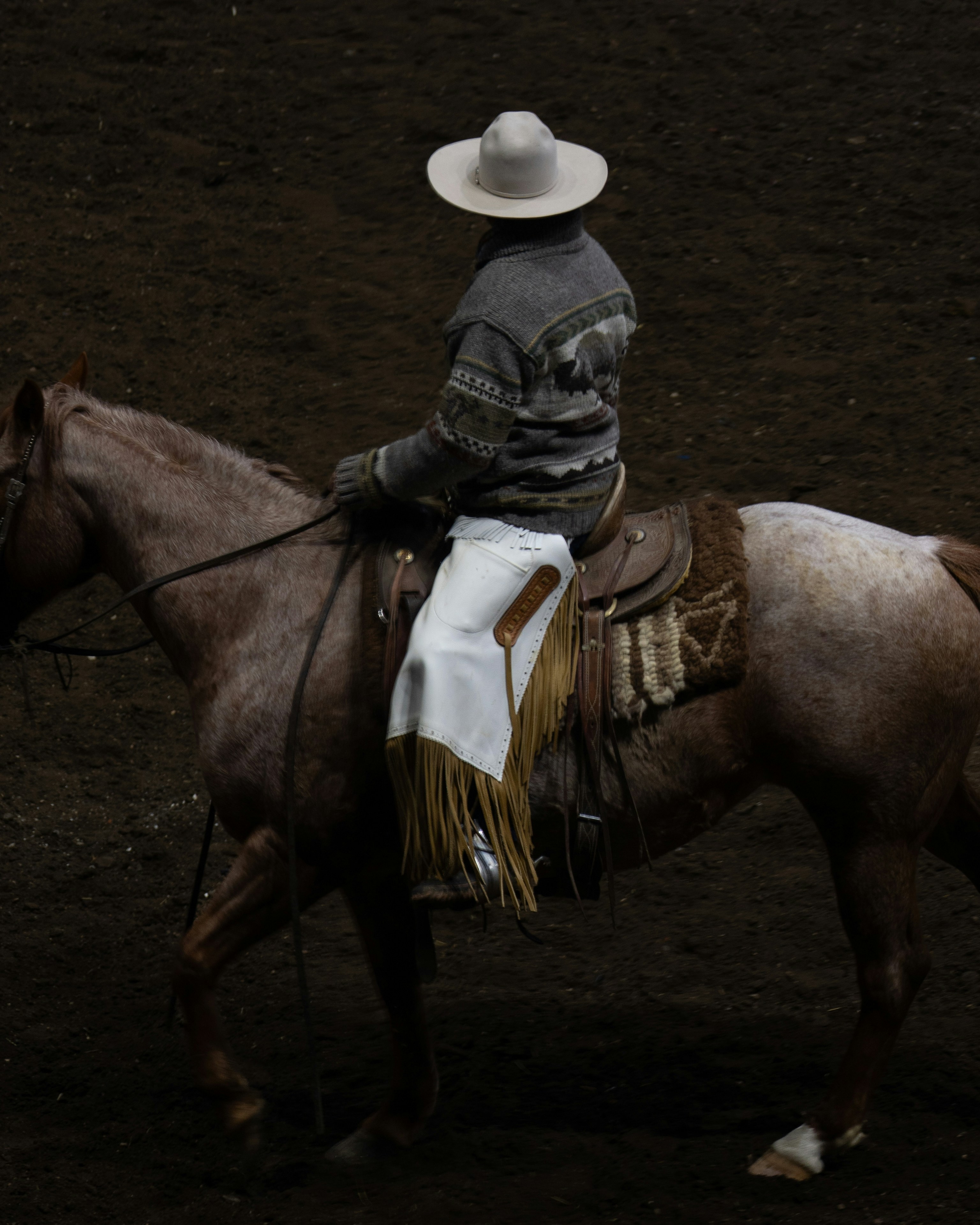 Mounted Rancher in a Fringed Tan Blanket: Quiet Focus on the Saddle