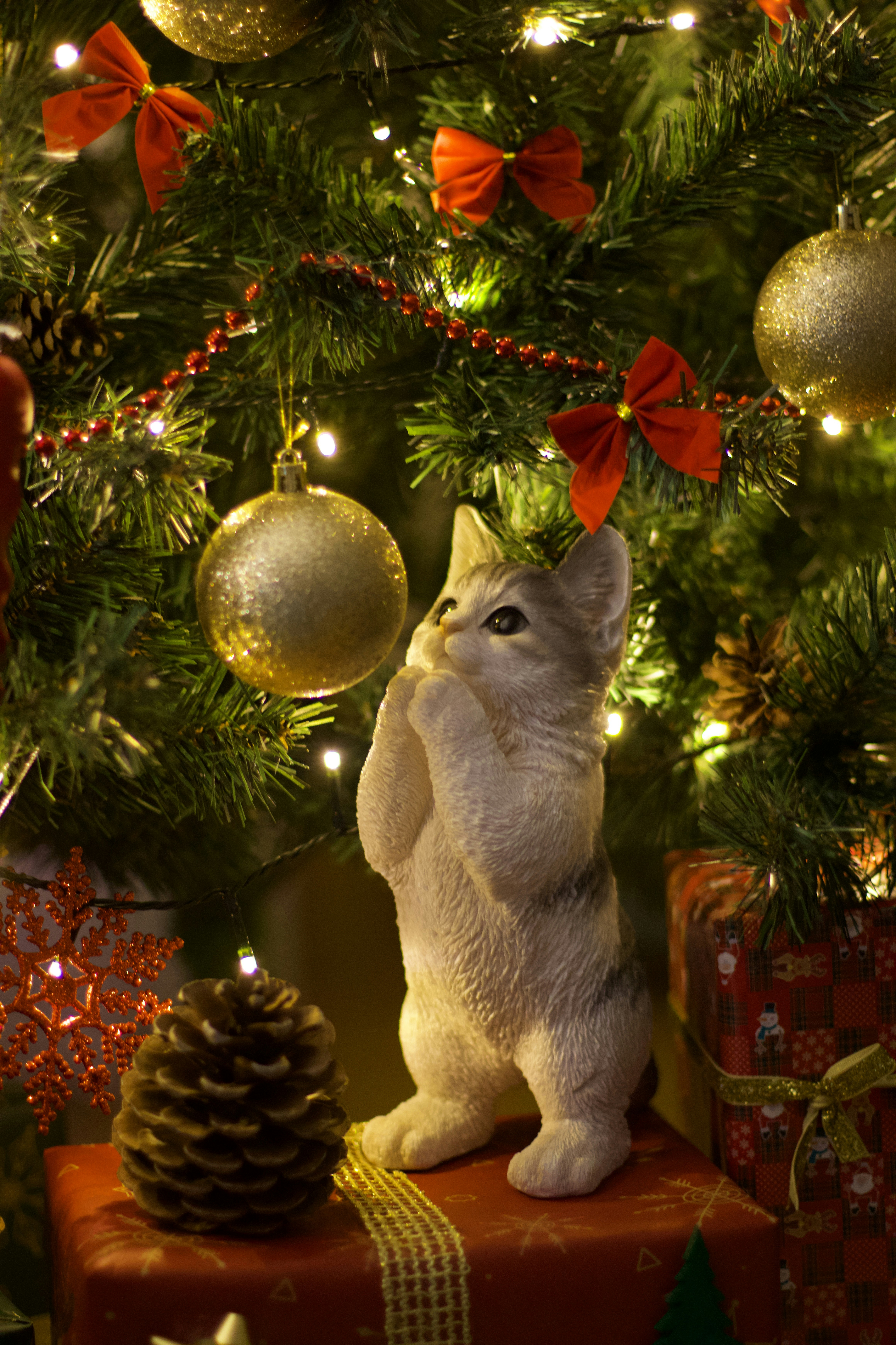 A christmas tree with decorations and a cat figurine.