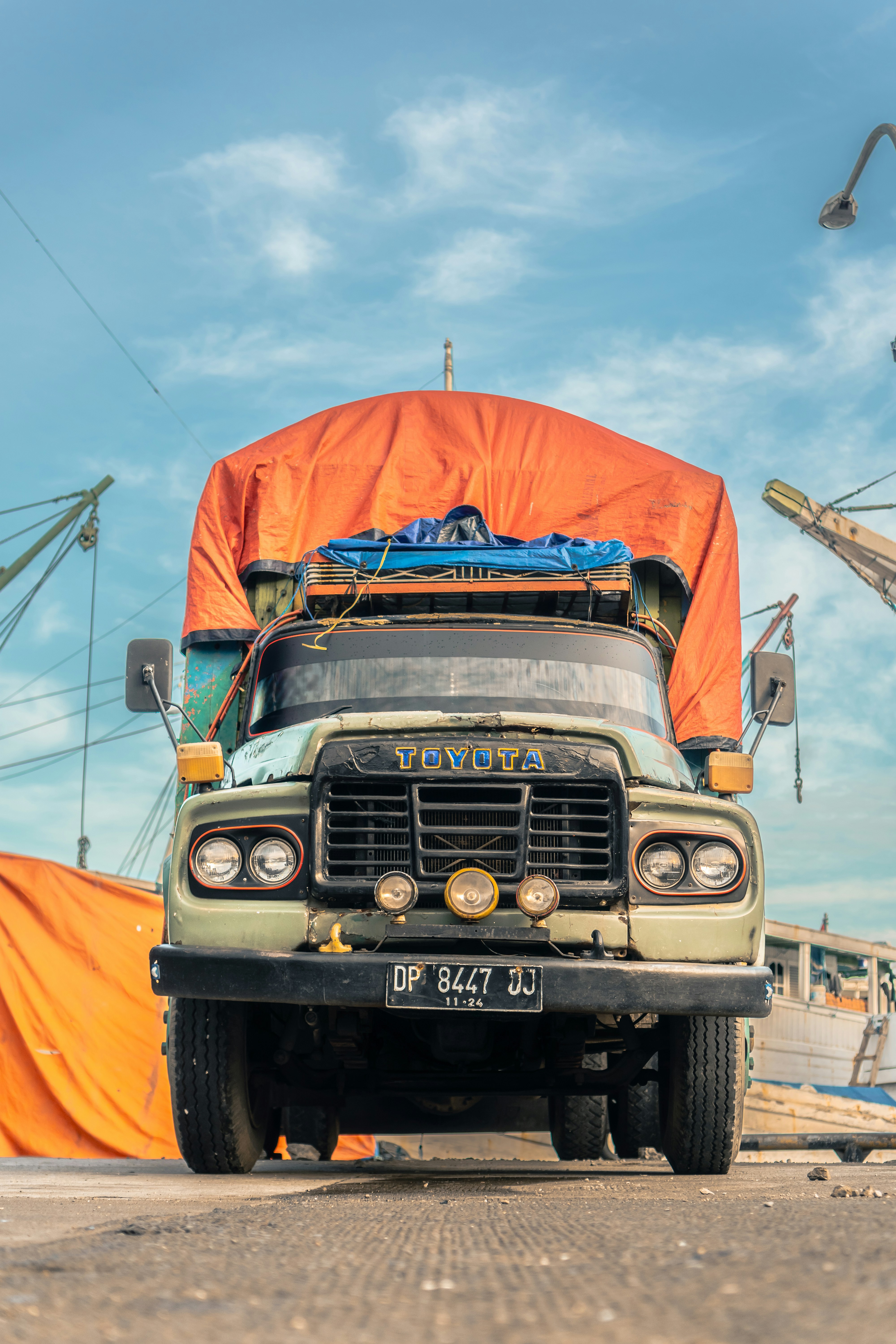 Front-Row Hauler: Weathered Toyota Under a Tangerine Tarpaulin in a Maritime Yard