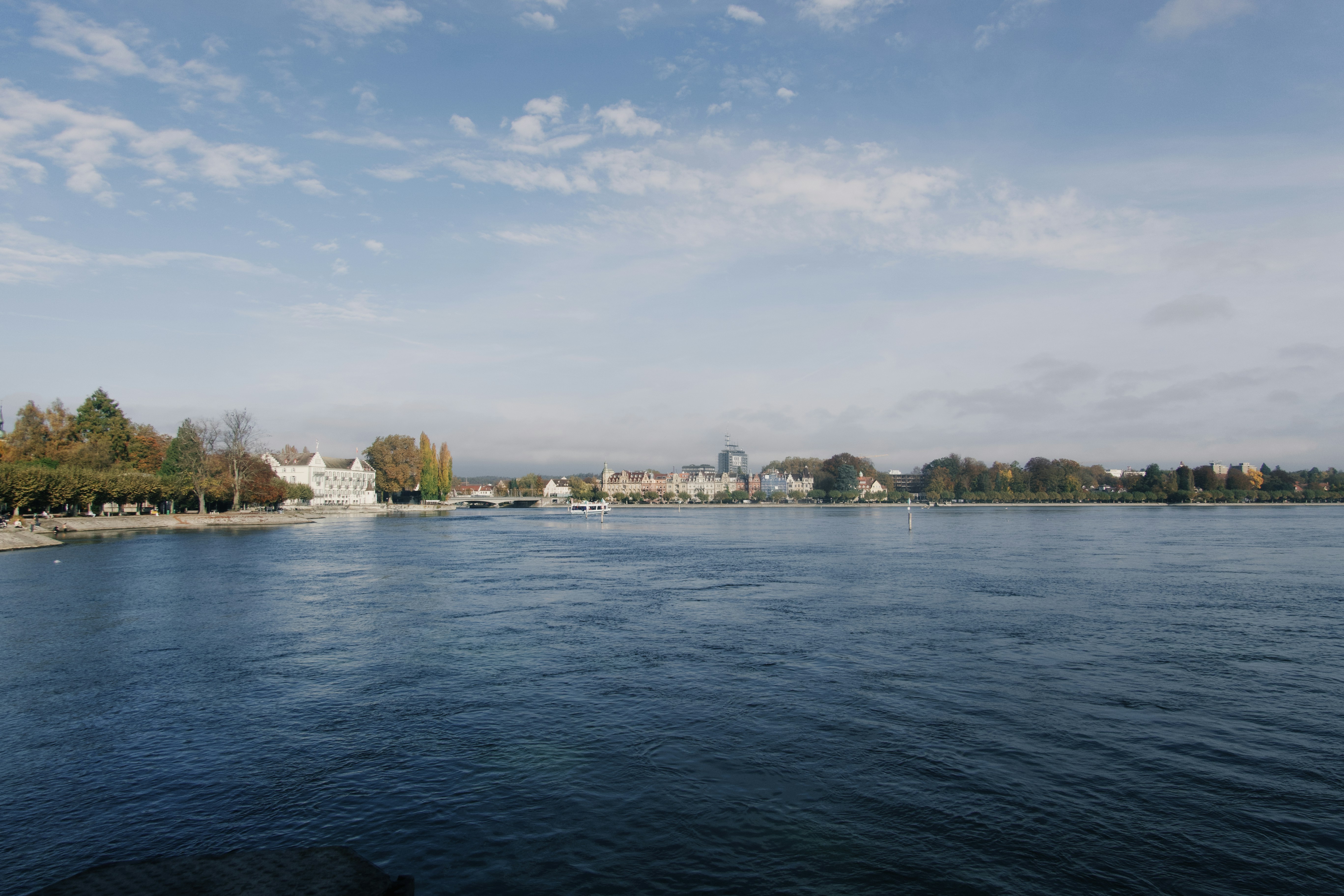 Tranquil waterfront townscape under a clear blue sky with autumn foliage.