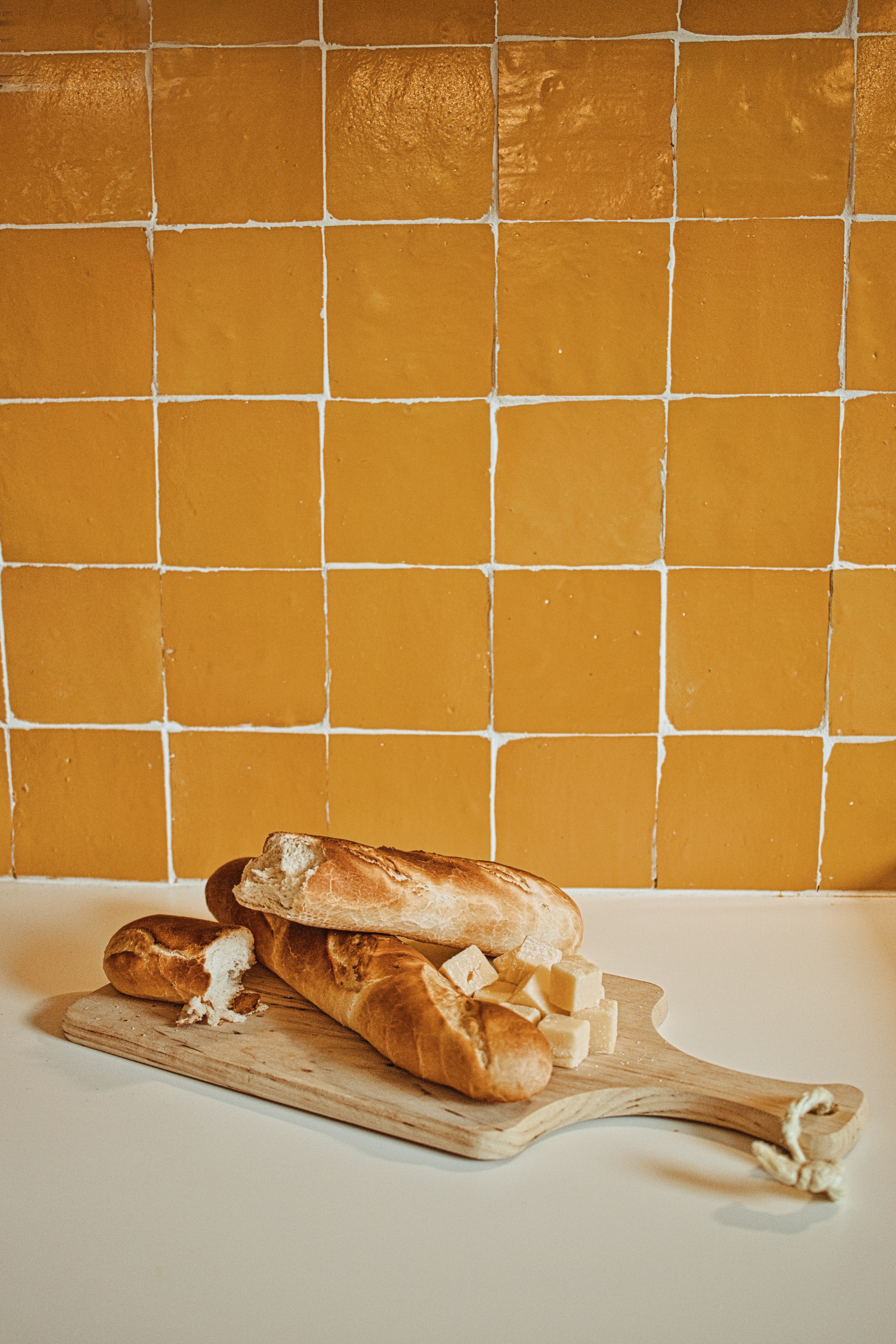 French baguette on white counter with yellow tiles in the background