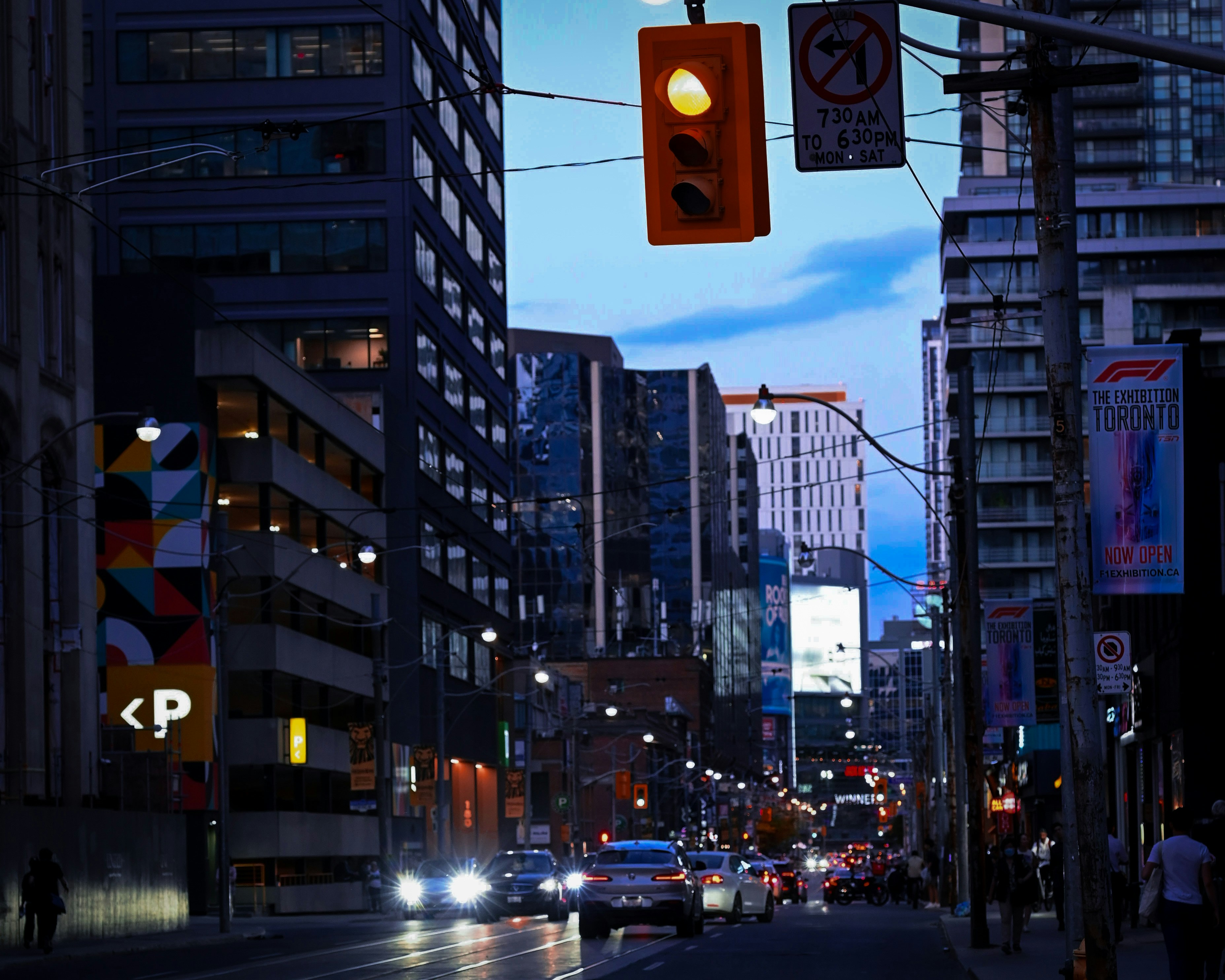 City street scene with glowing traffic lights and buildings silhouetted against a twilight sky.