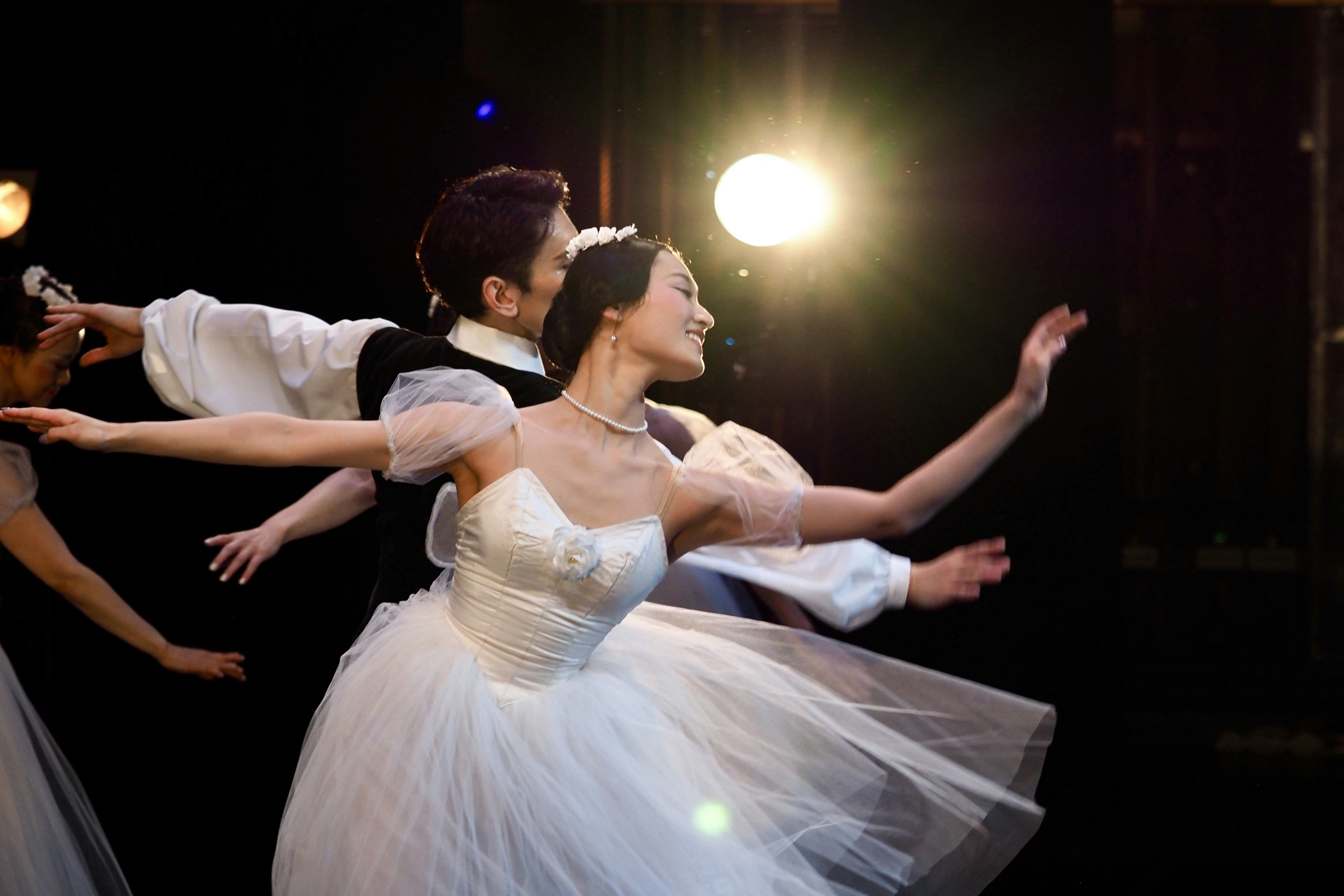 Ballet dancers elegantly poised on stage with soft lighting highlighting their movement.