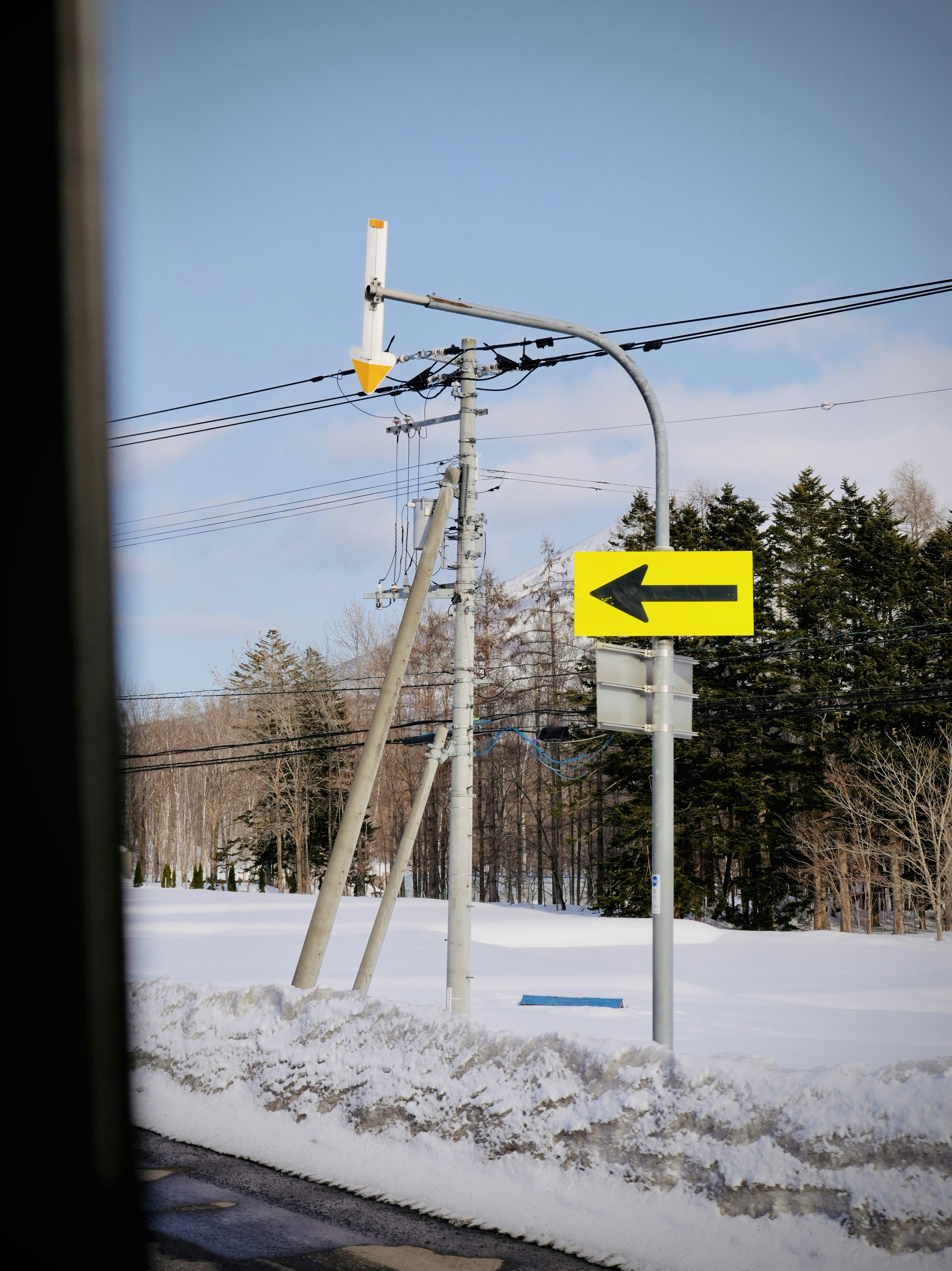 Winter Intersection: Yellow Arrow Sign Amid Bent Poles and Snow