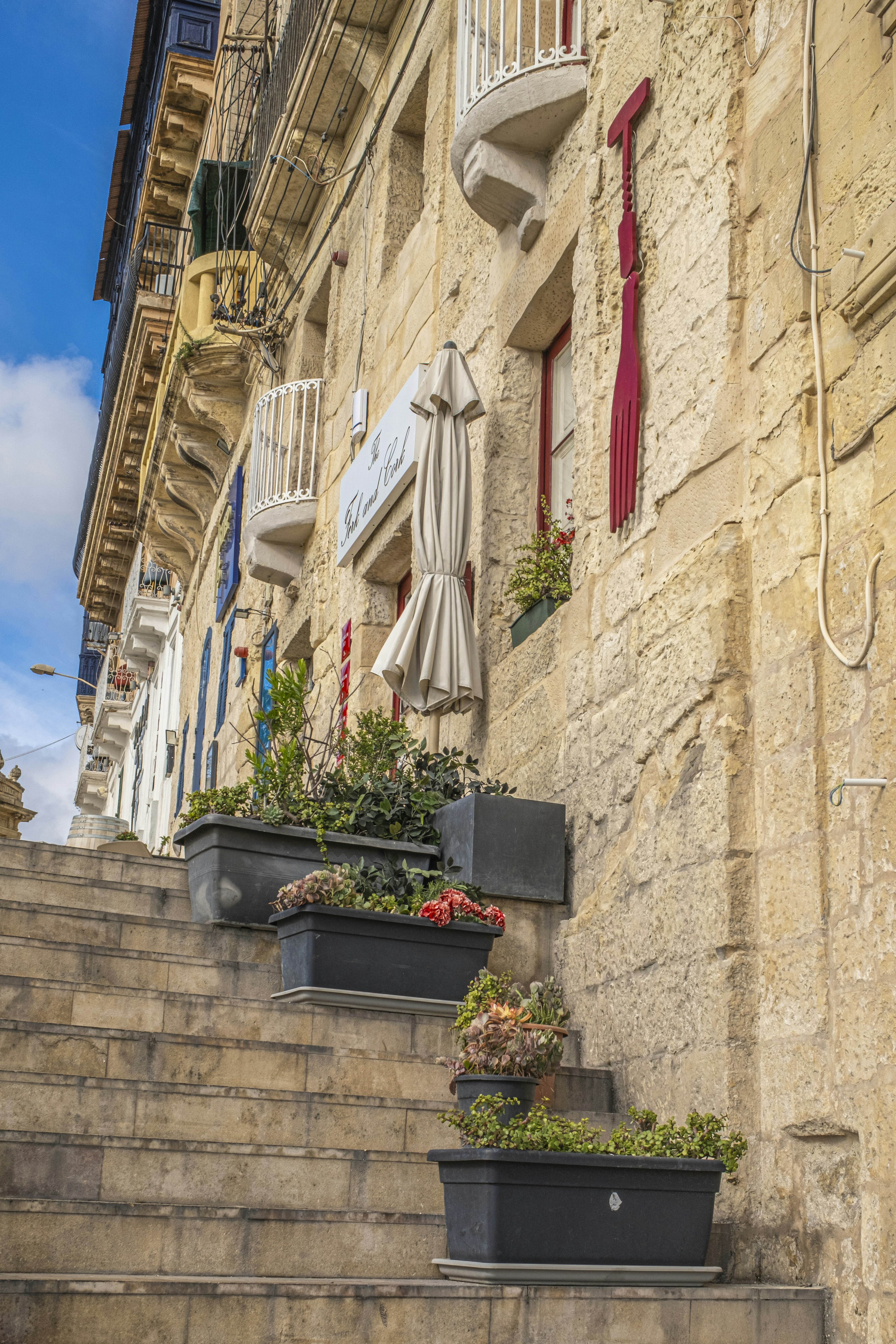 Terraced Planters Climb a Sunlit Limestone Facade