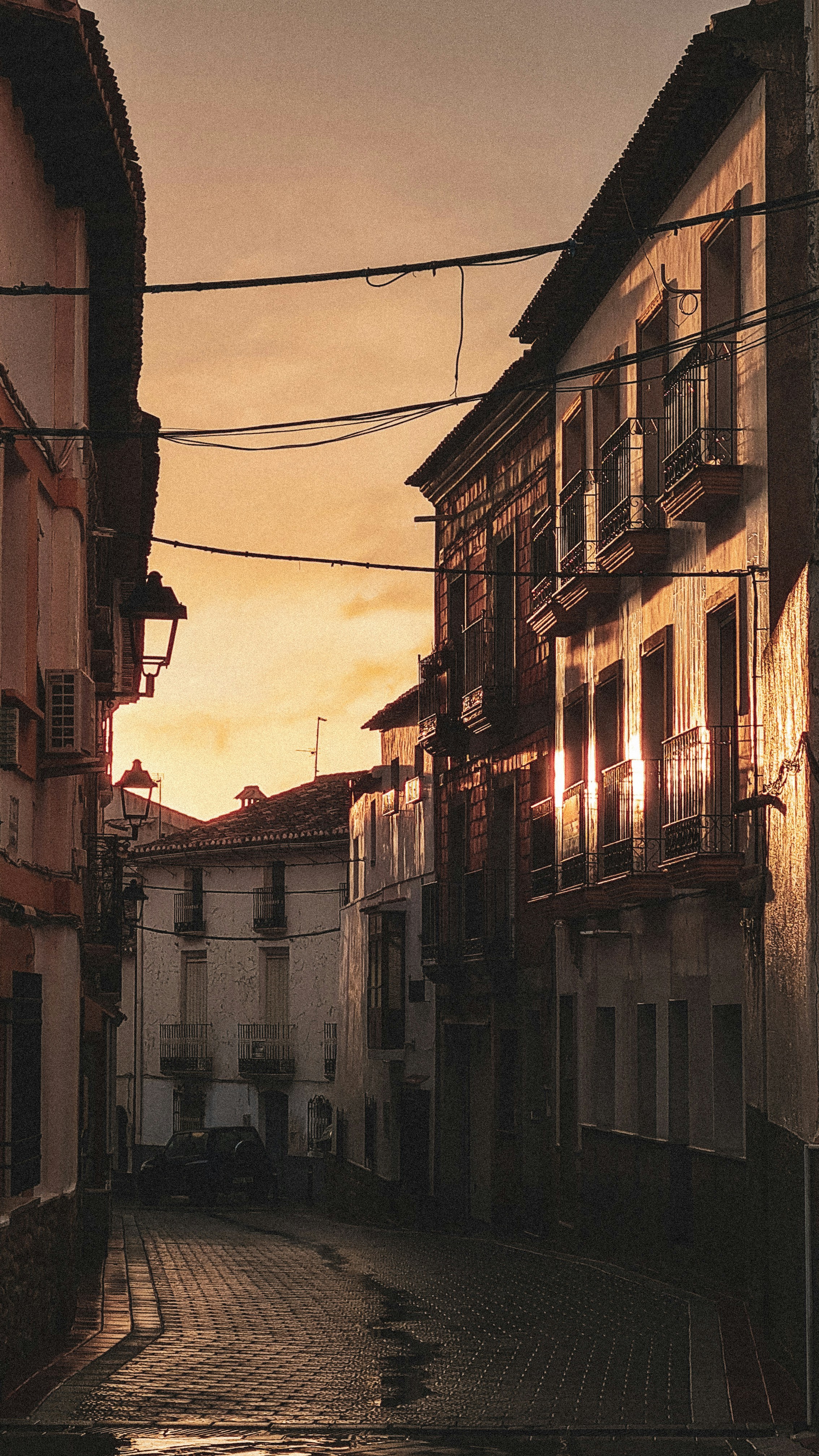 Narrow street bathed in warm sunset light with historic buildings reflecting the glow.