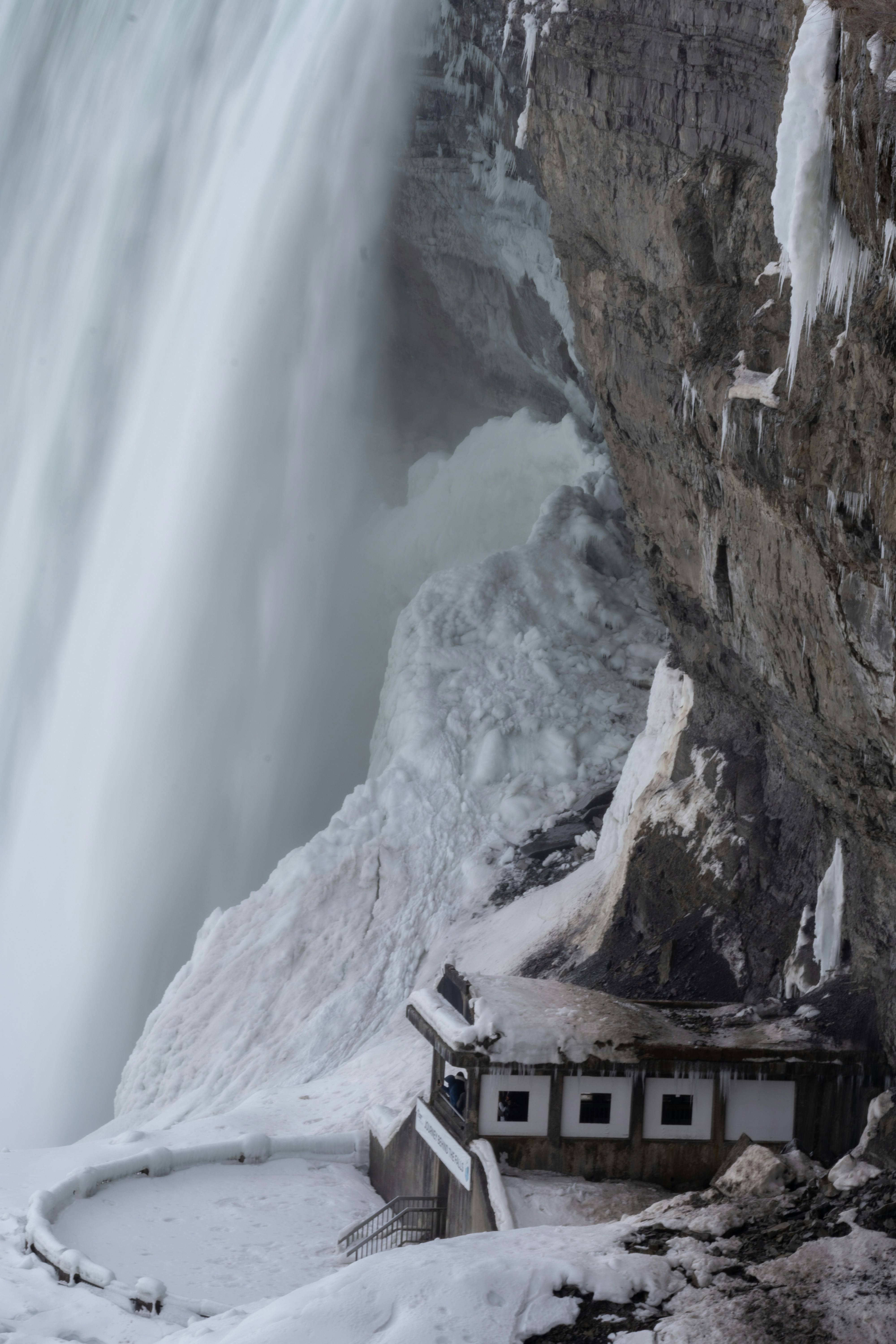 A small building faces a massive waterfall. photo – Free Snow Image on ...
