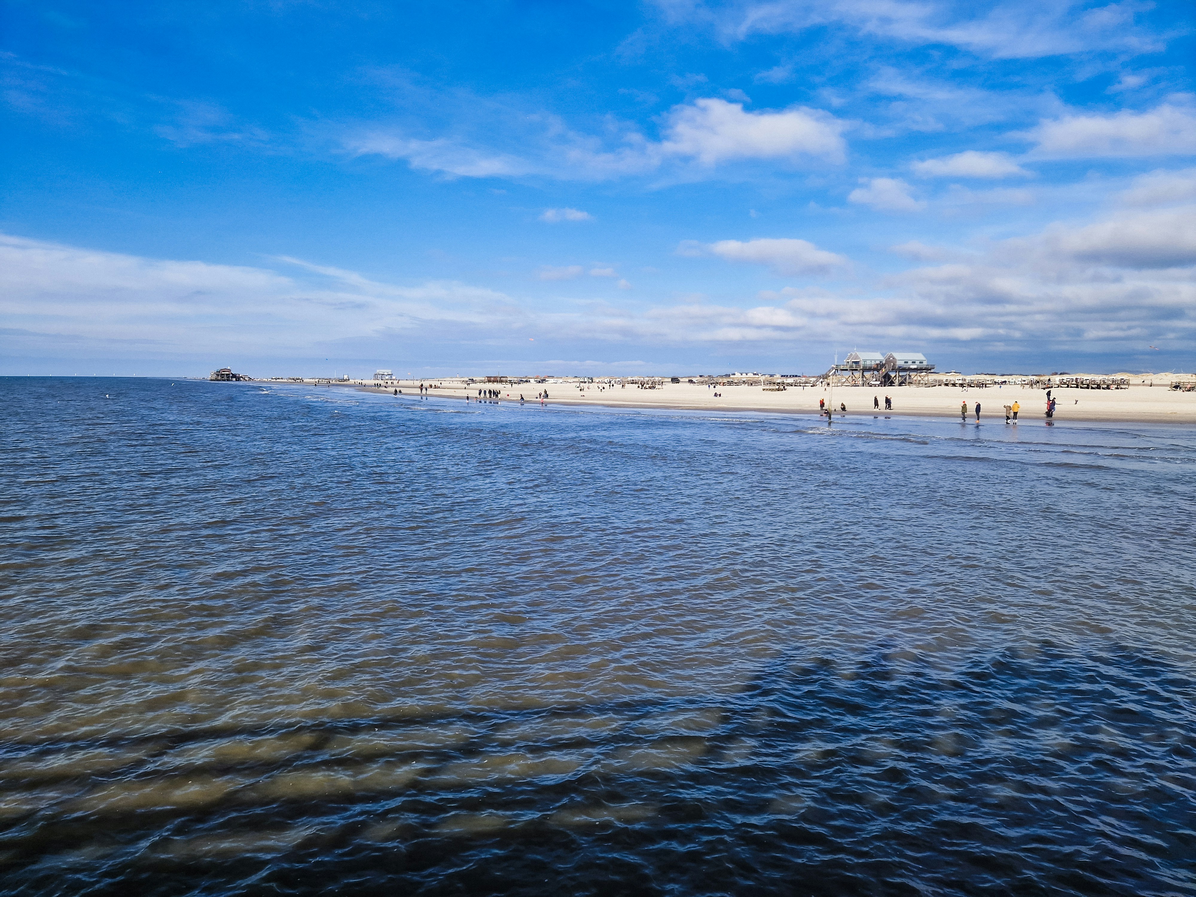 Expansive beach with gentle waves under a vibrant blue sky.