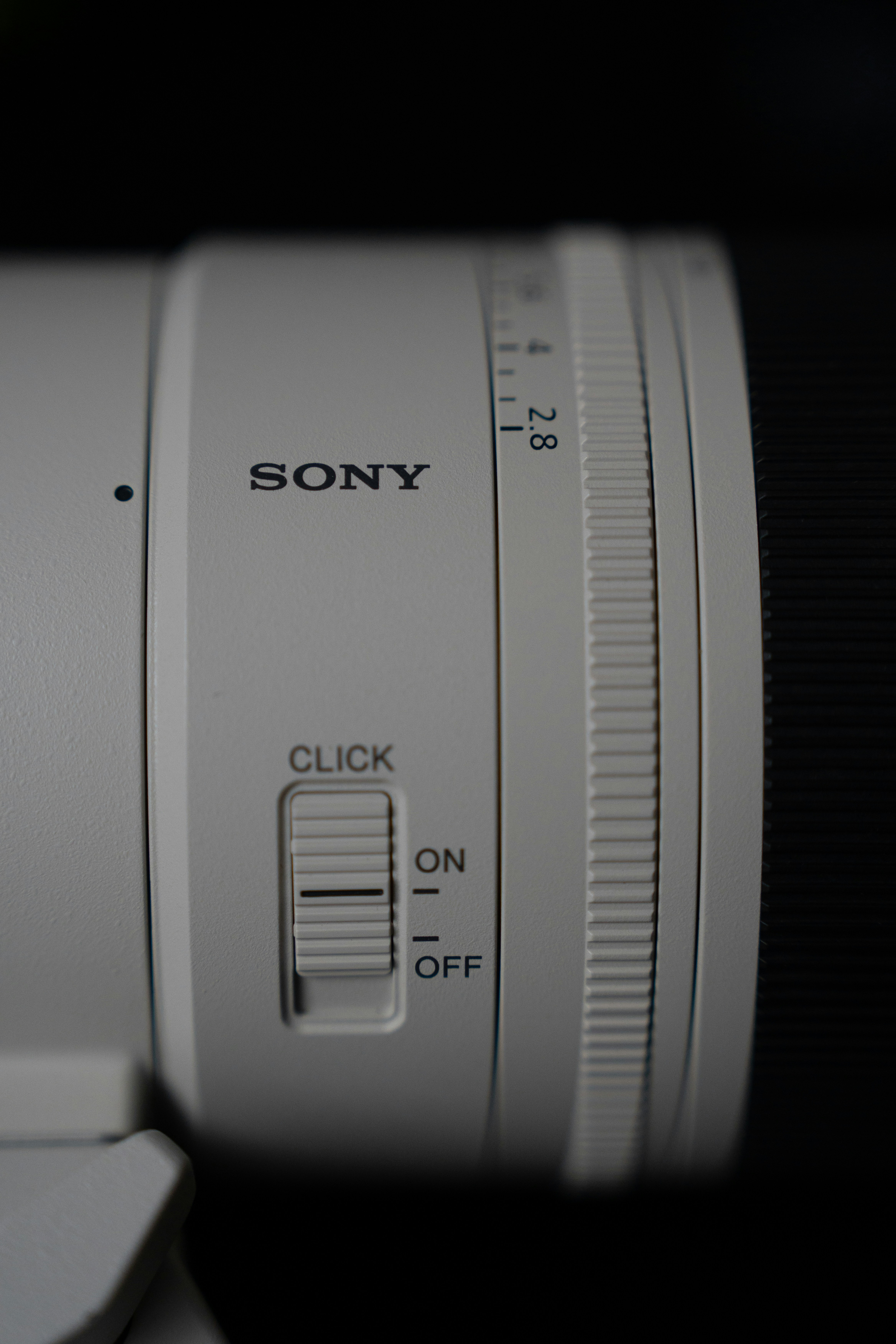 Close-up of a white camera lens with focus and zoom rings, featuring Sony branding.