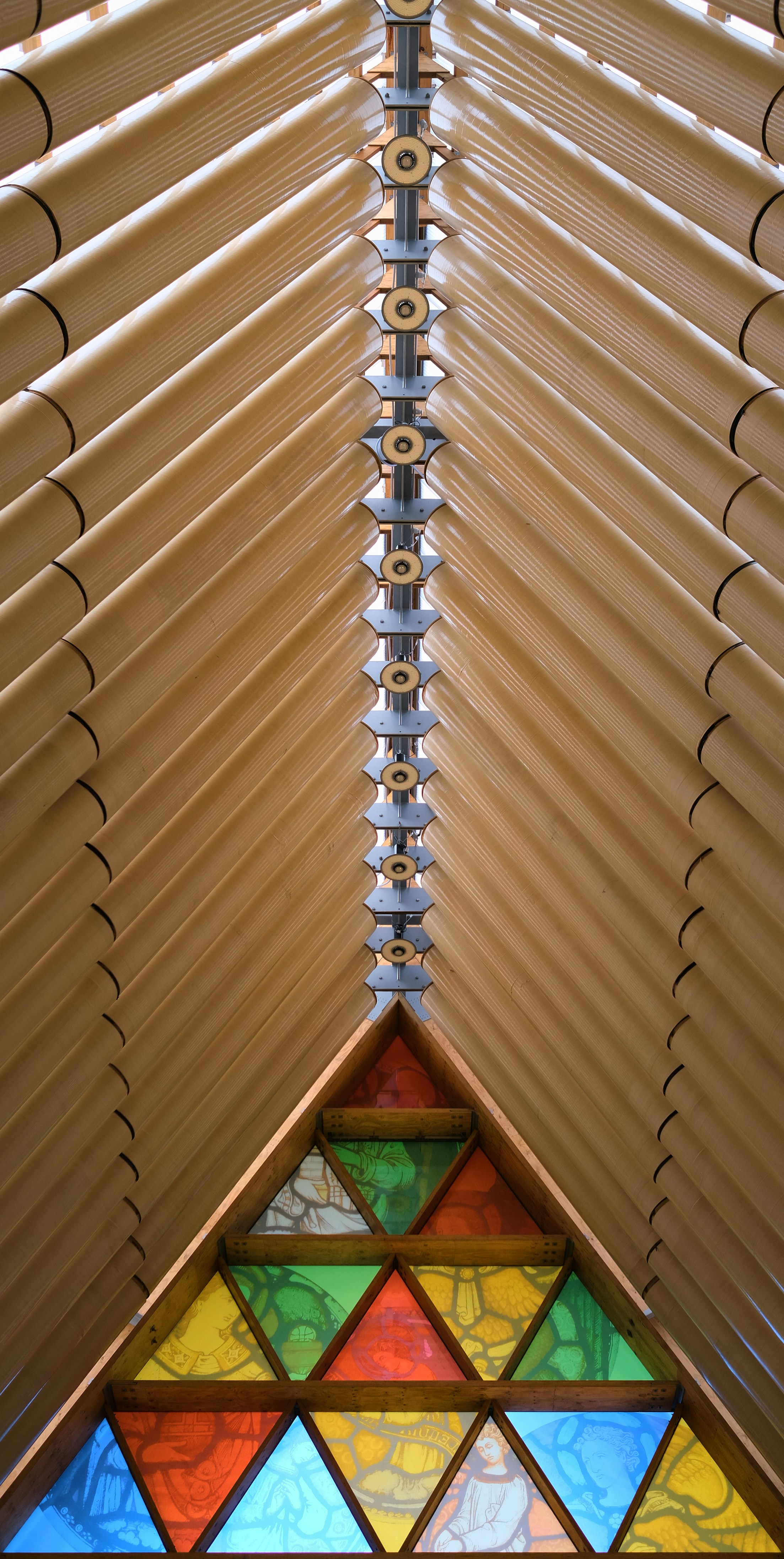 Architectural interior showcasing a unique ceiling design with bamboo-like elements and vibrant stained glass patterns.
