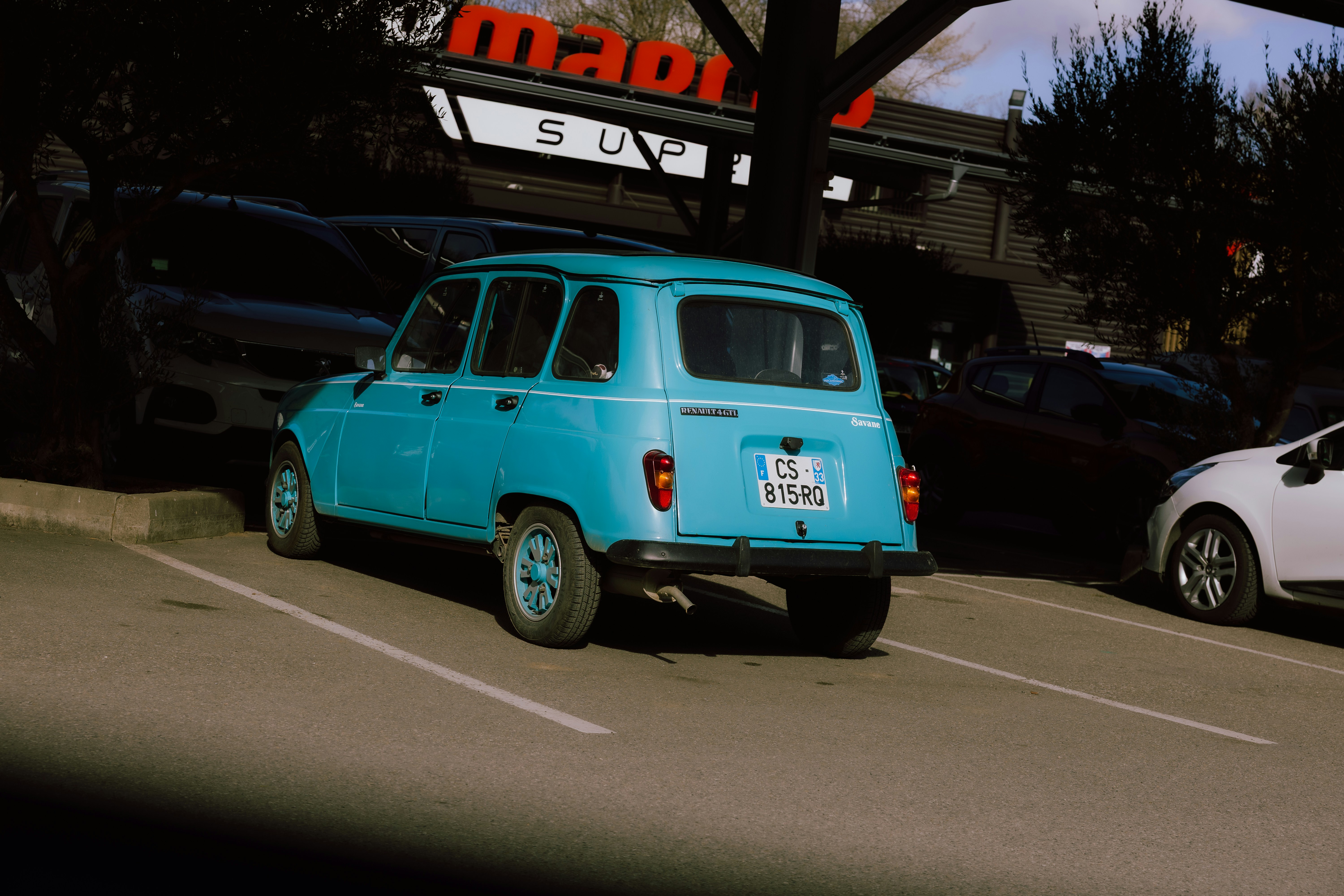 Azure Vintage Microcar Reposed in a Sunlit Mall Parking Lot