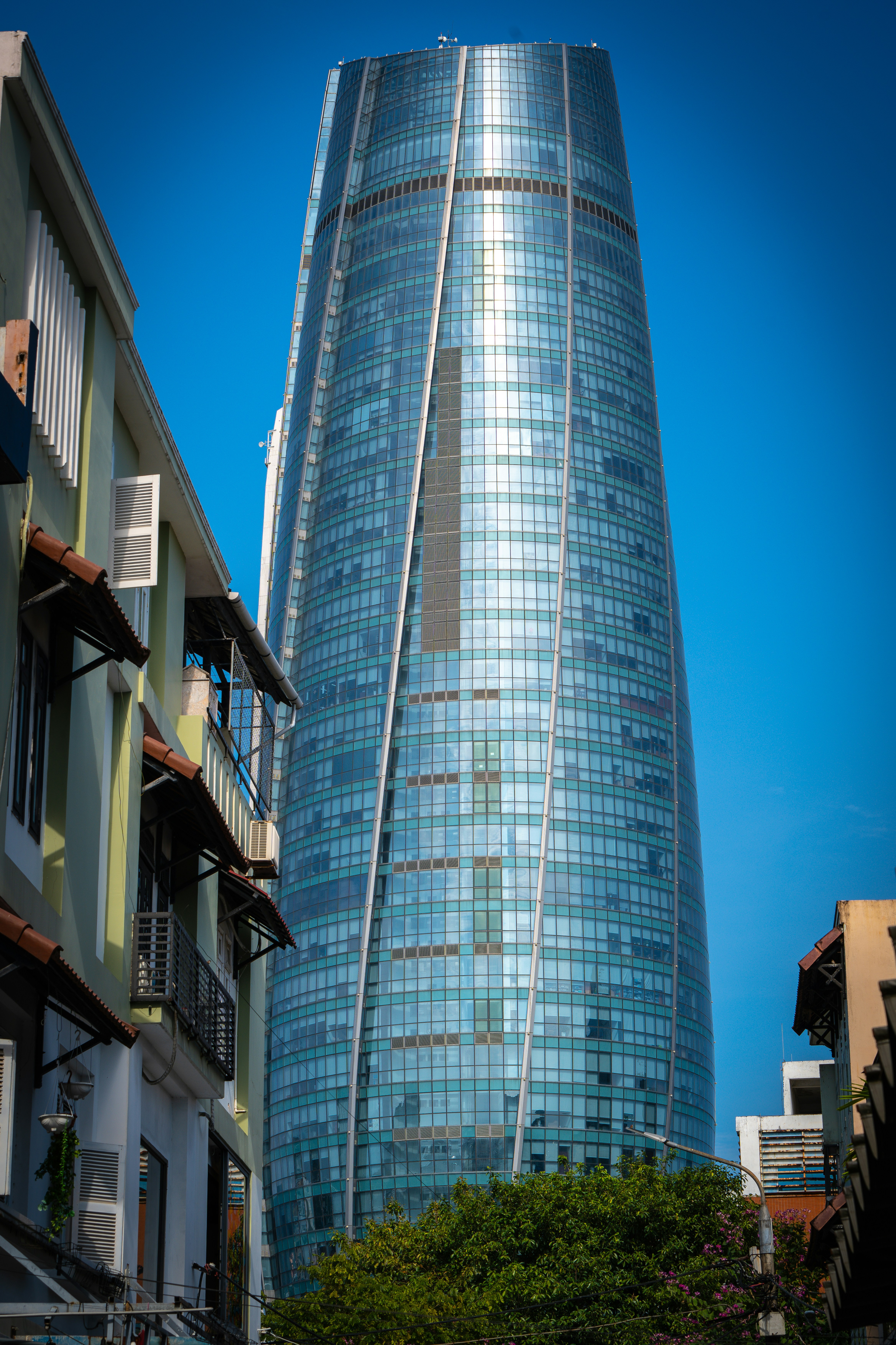 A tall, modern skyscraper towers above city buildings. photo – Free ...
