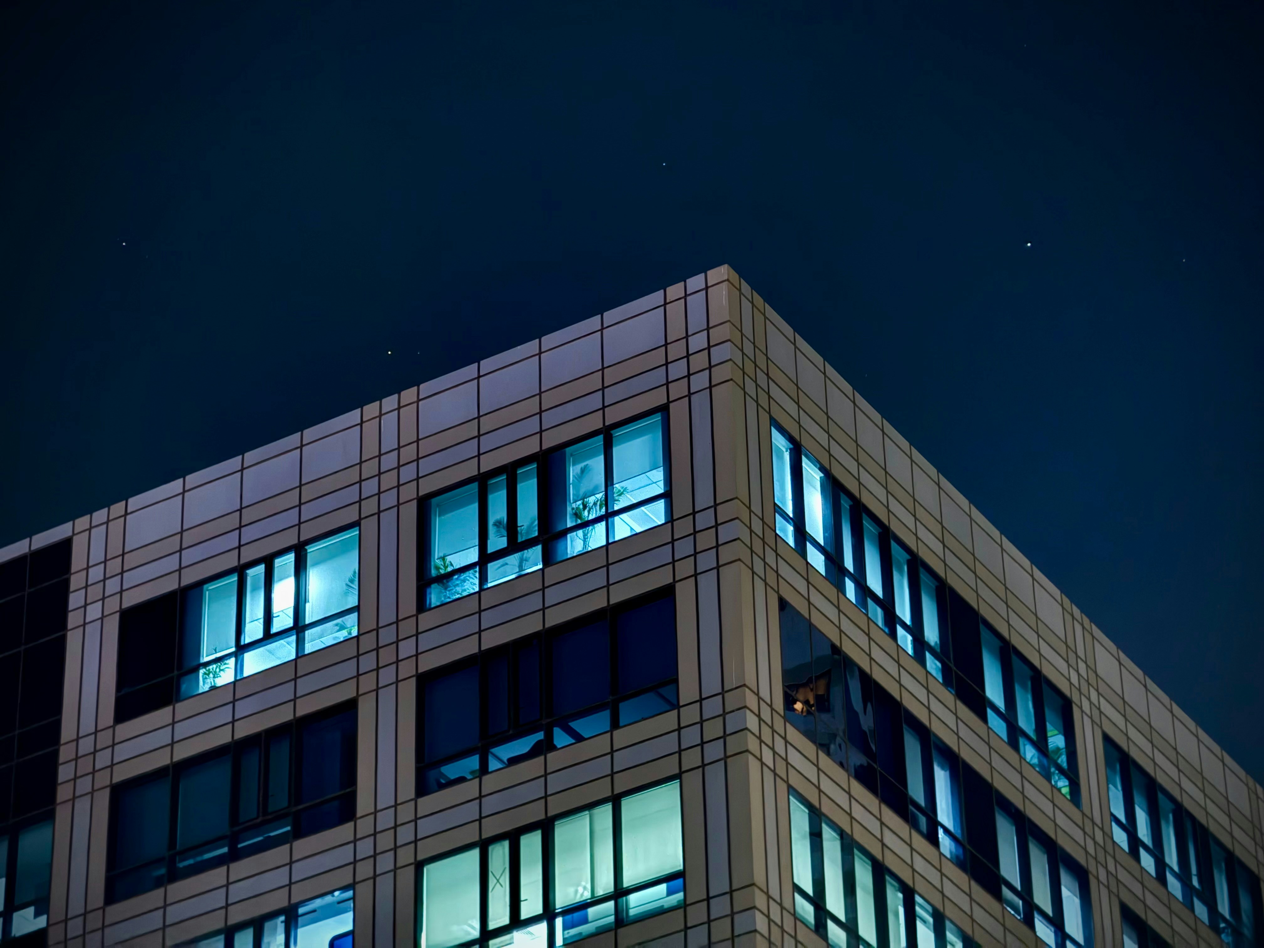 Office building illuminated at night with a few stars.