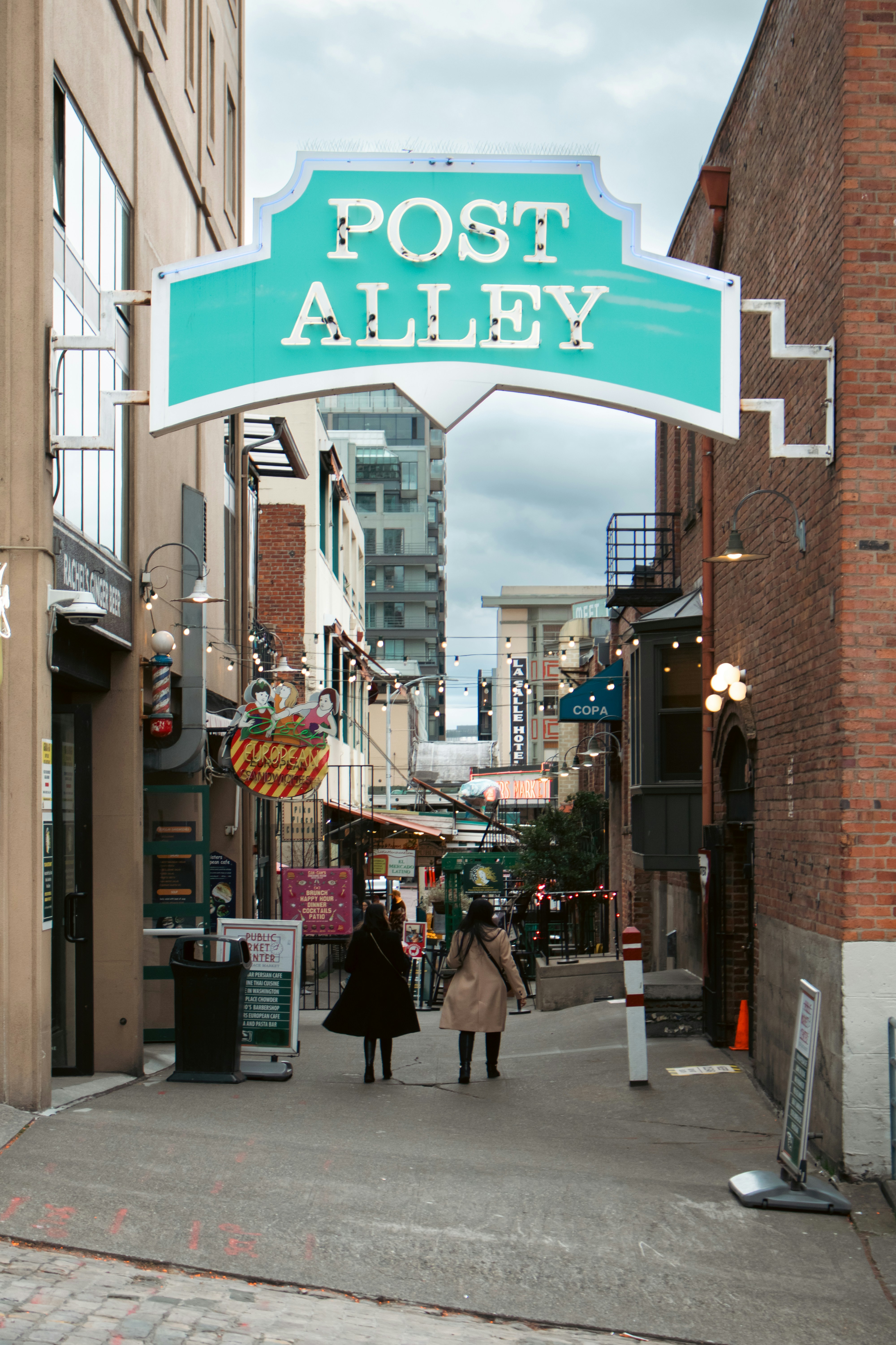 Teal Post Alley Arch Over a Bustling Urban Lane