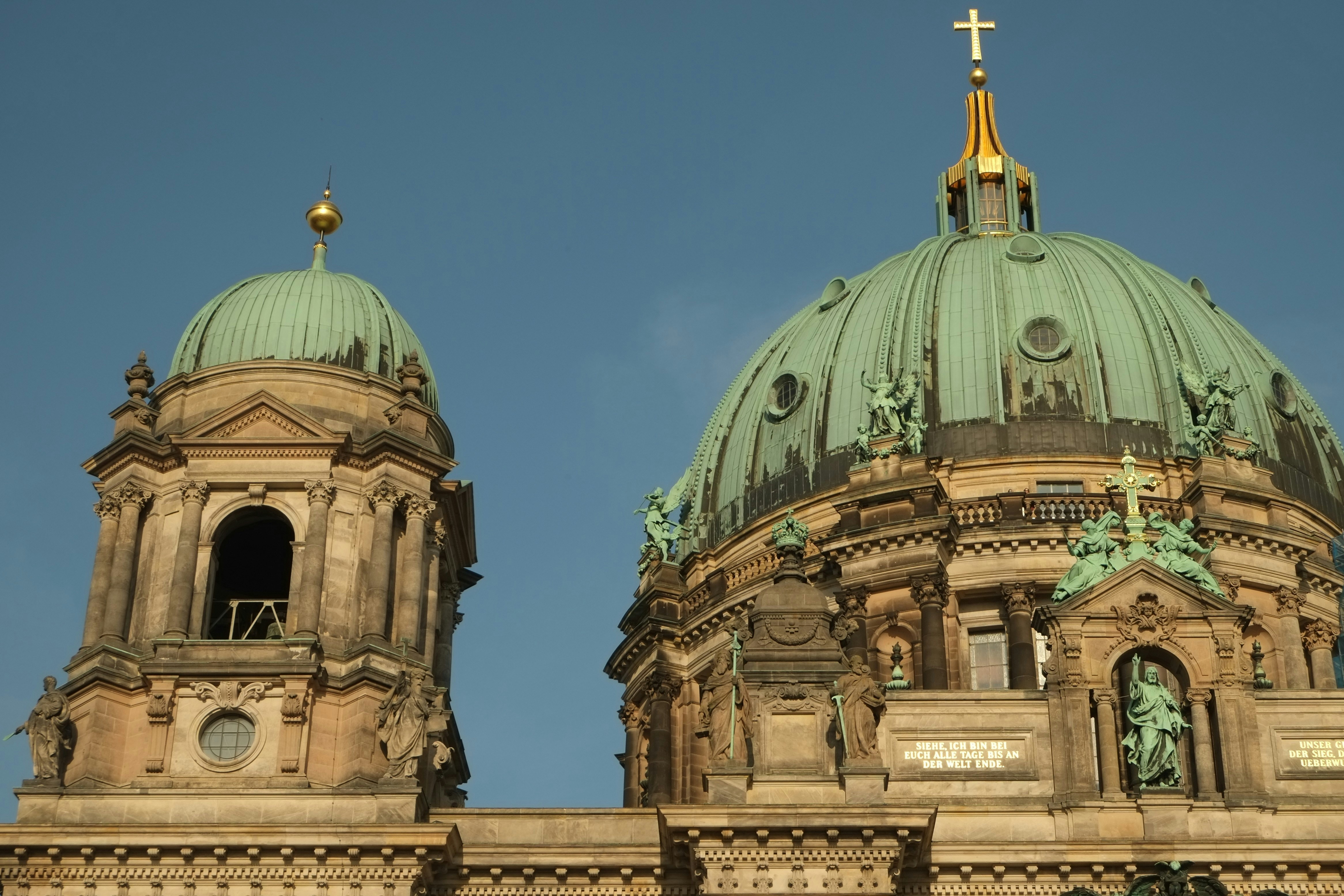 Ornate domes of Berlin Cathedral under a clear blue sky.