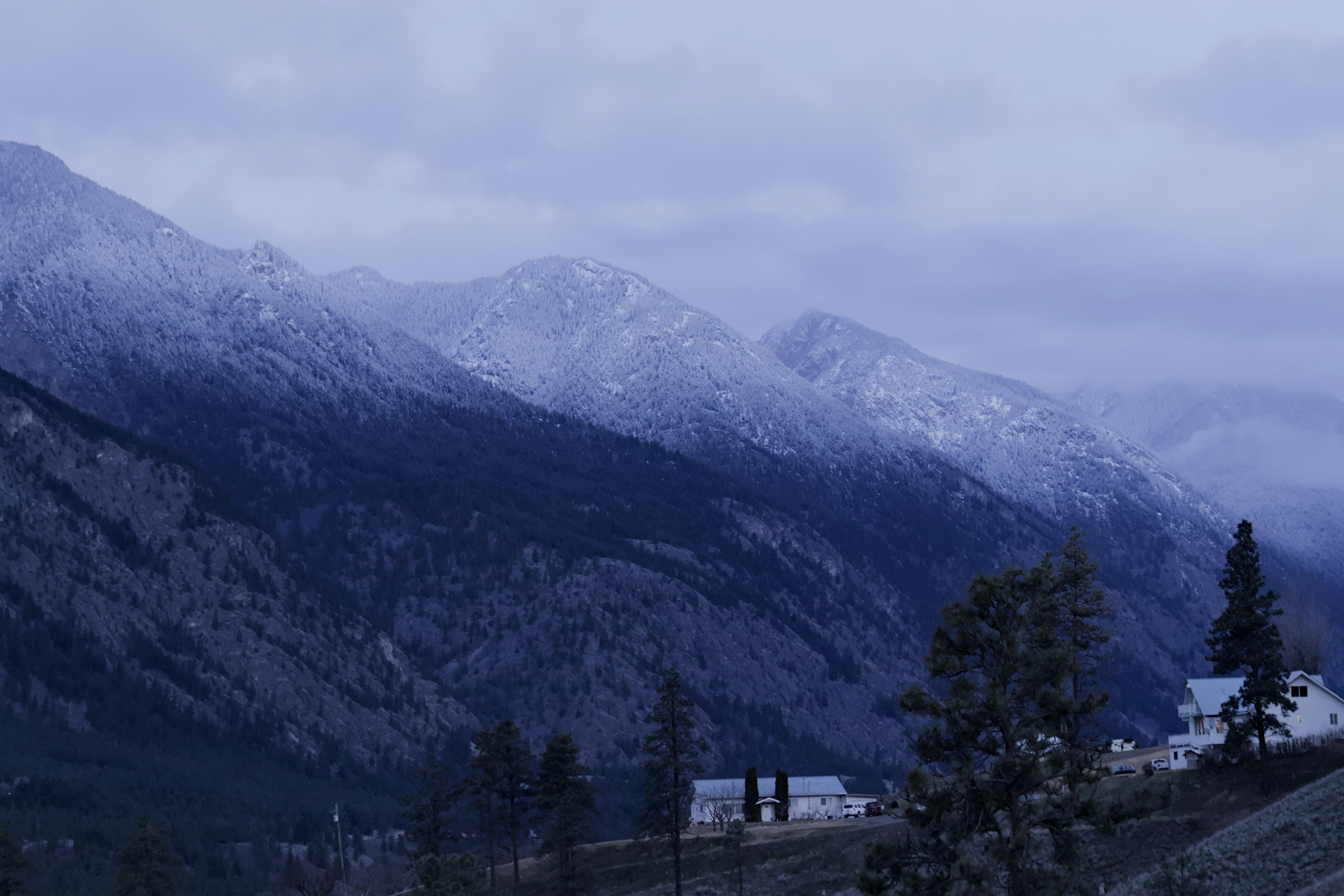 Snow-capped mountains loom under a cloudy, dusky sky. photo – Free ...