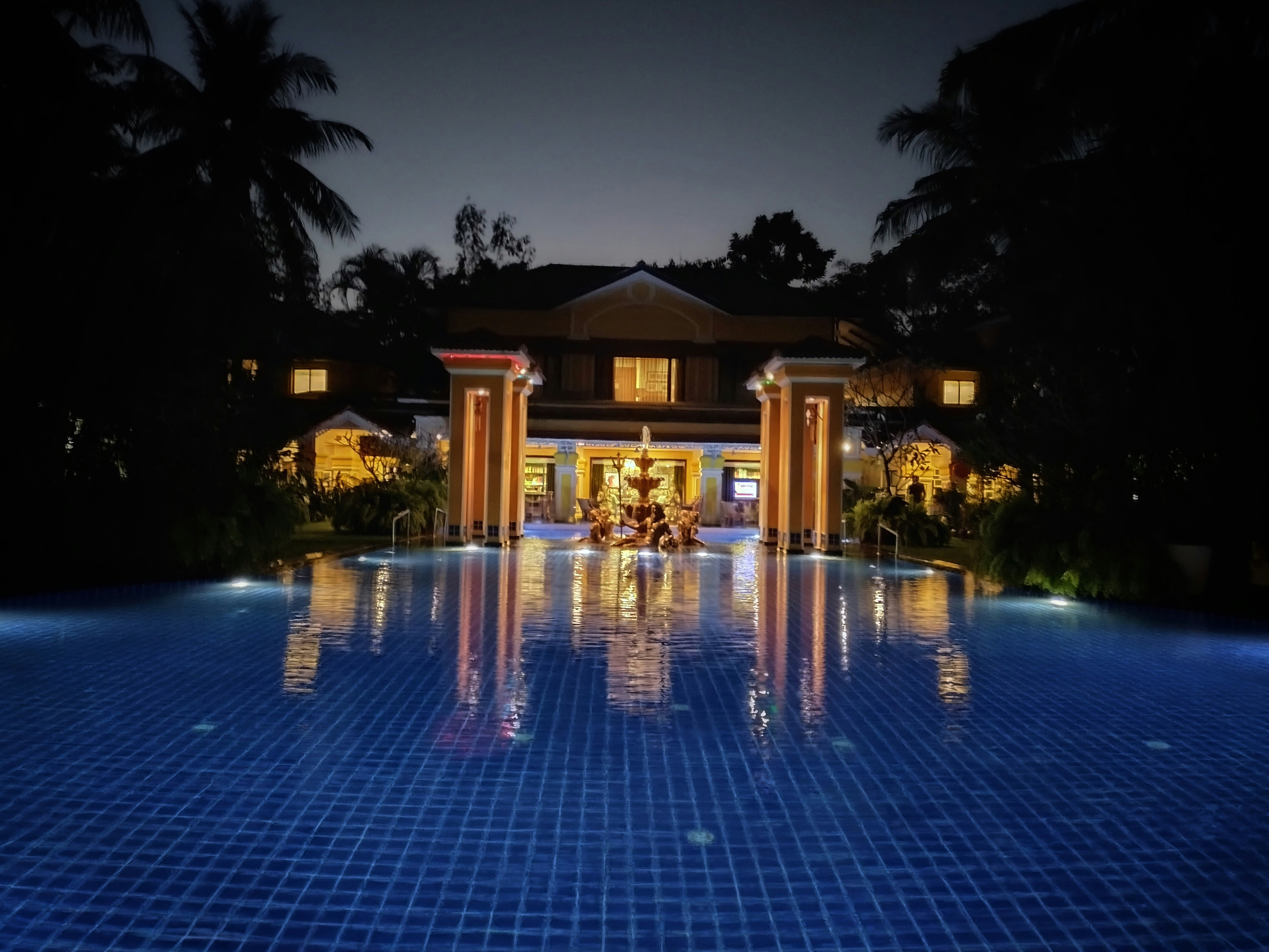 Lit-up pool reflects a beautiful building at night. photo – Free ...