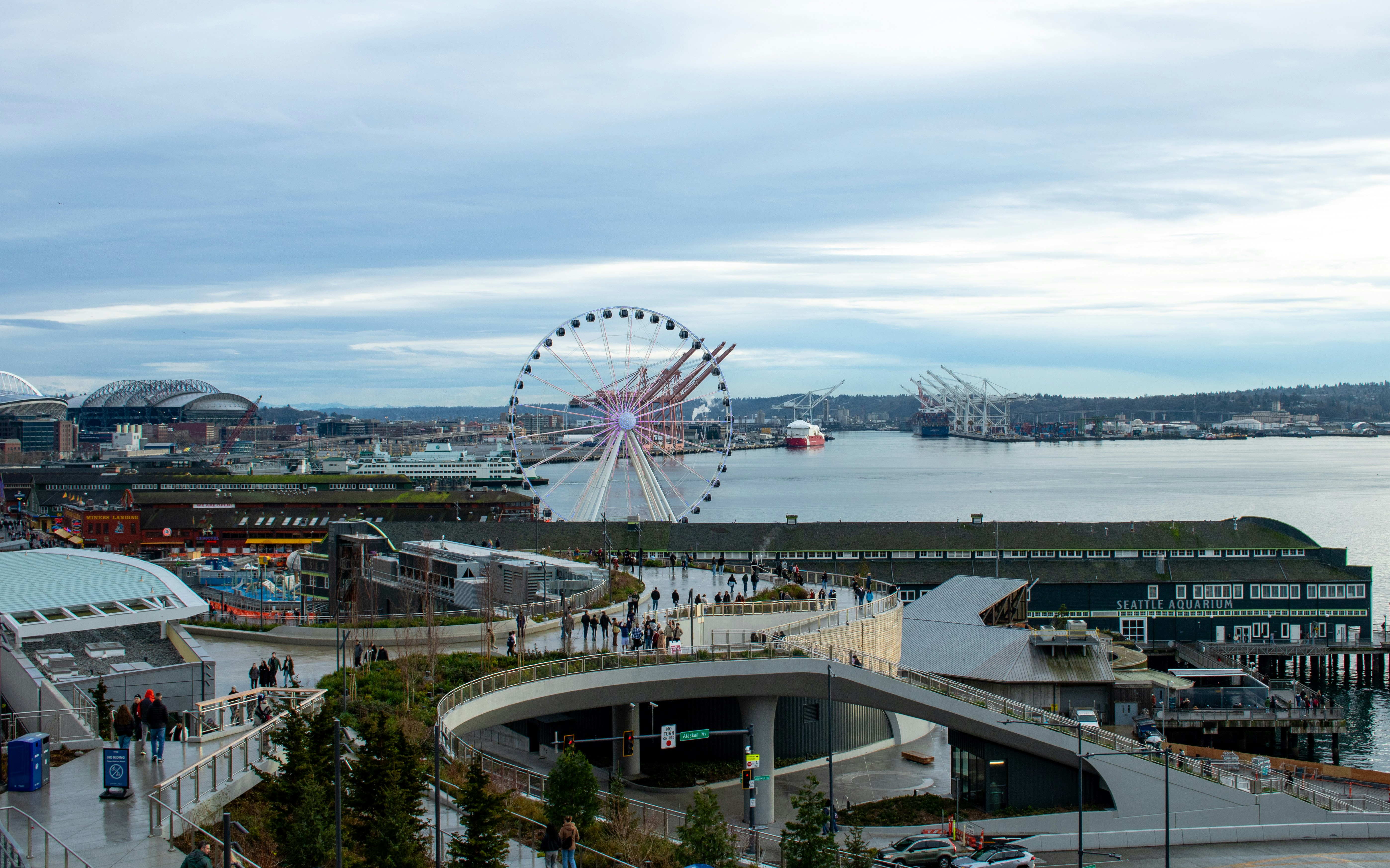 Seattle waterfront with a winding pedestrian path, ferris wheel, and skyline views.