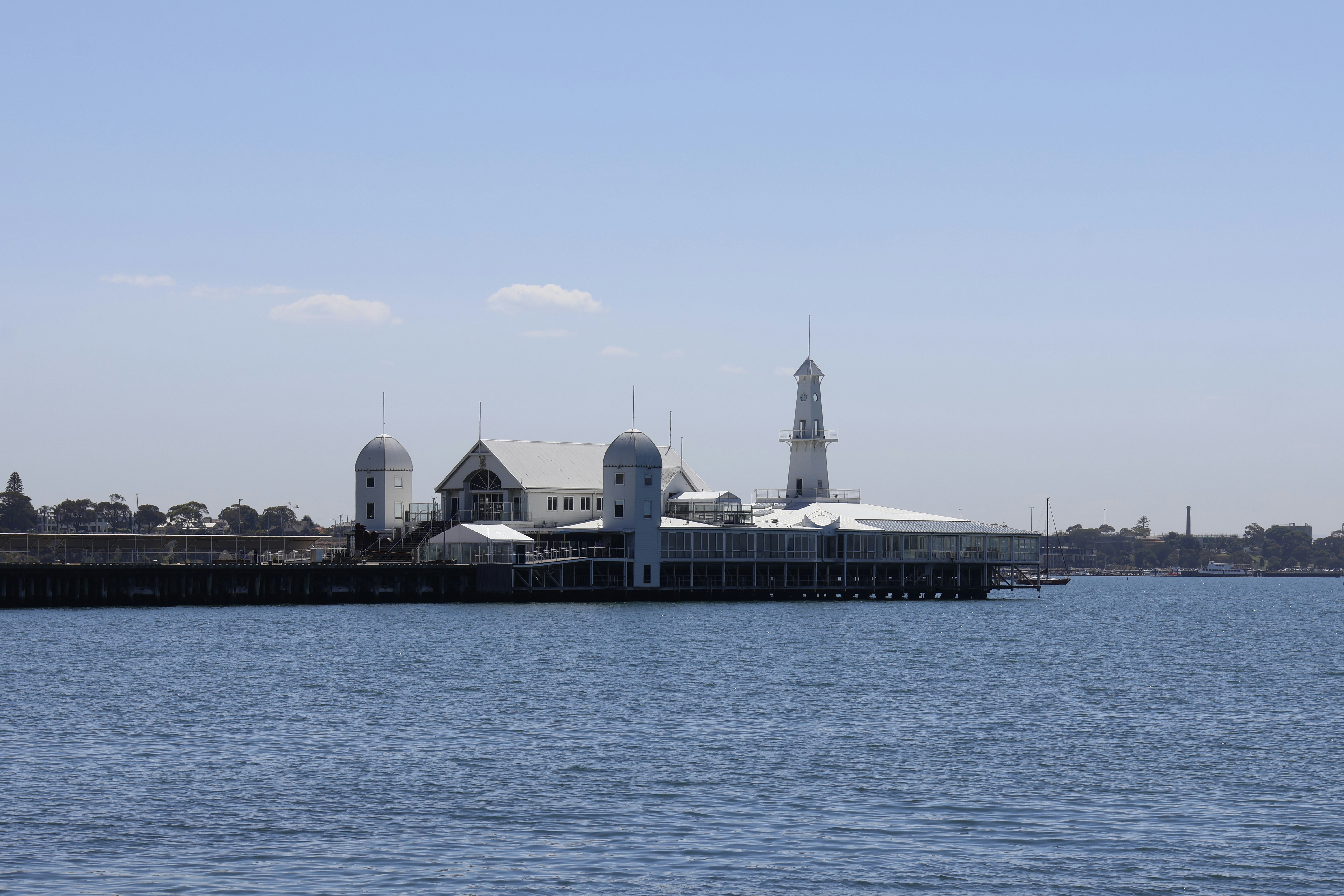 White waterfront structure with towers overlooking tranquil blue waters under a clear sky.