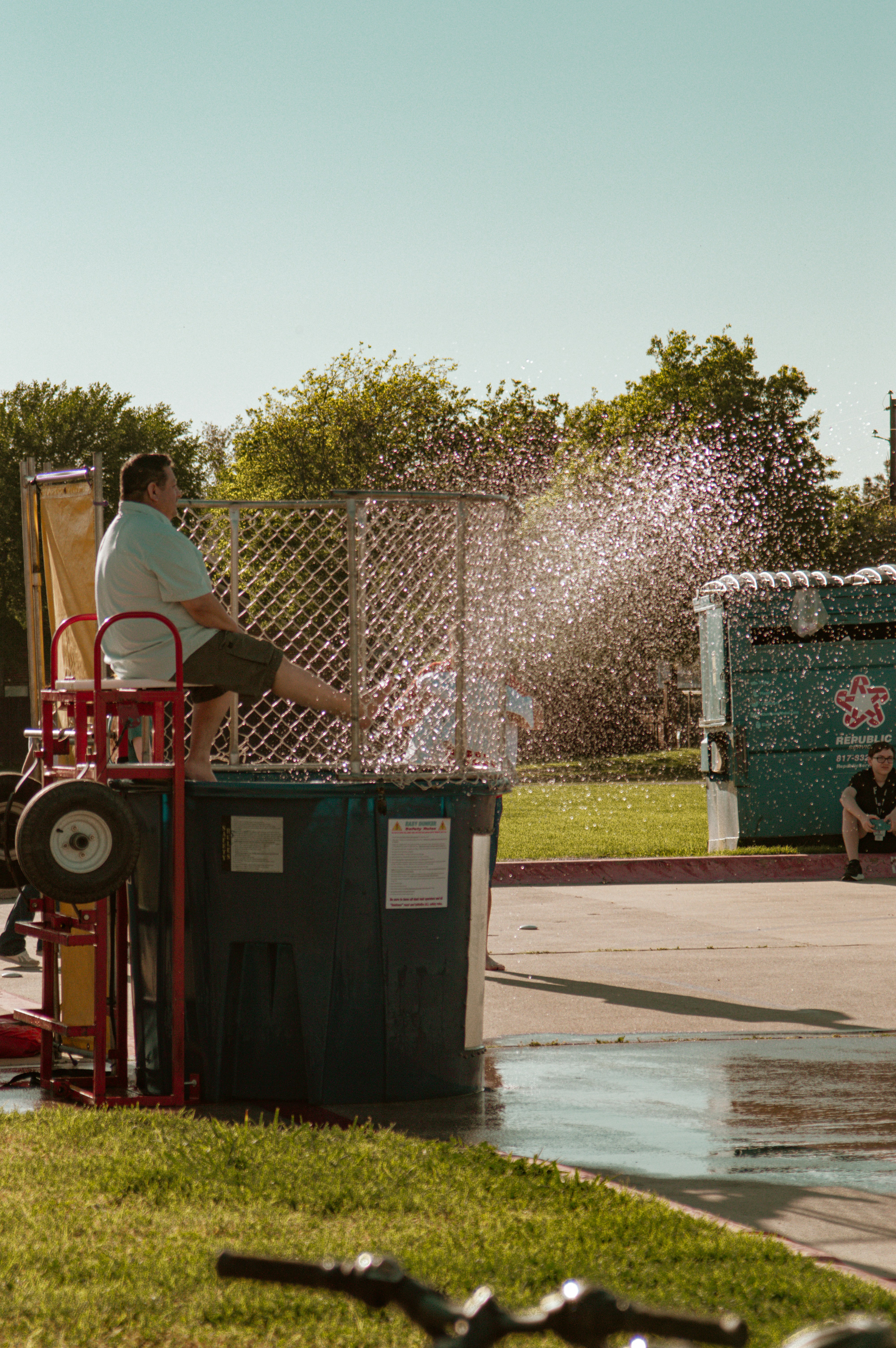Sunlit Dunk-Tank Operator Sprays Water from a Raised Platform