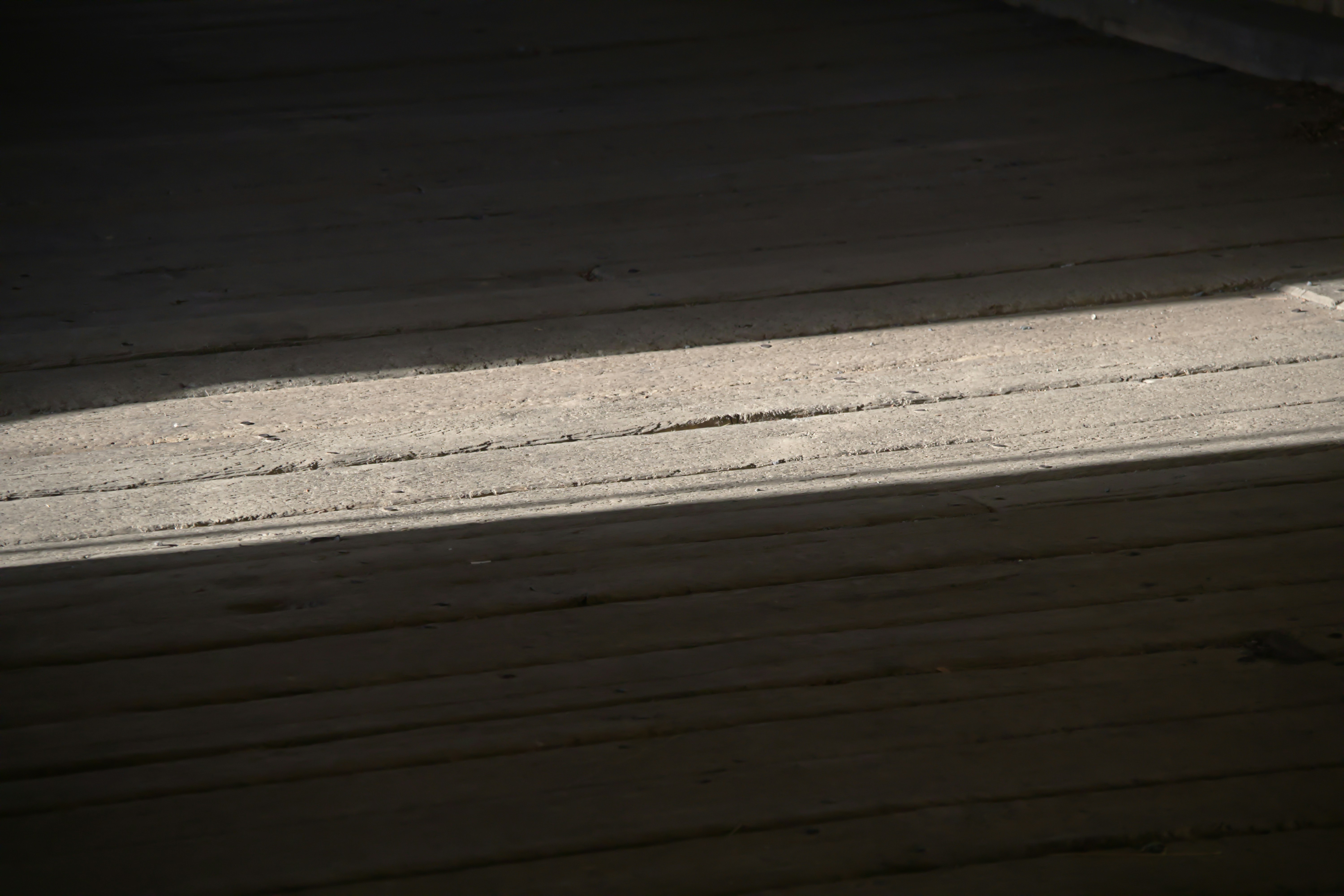 Sunlight casts a delicate beam across the textured surface of aged wooden planks, highlighting their natural grain and imperfections.