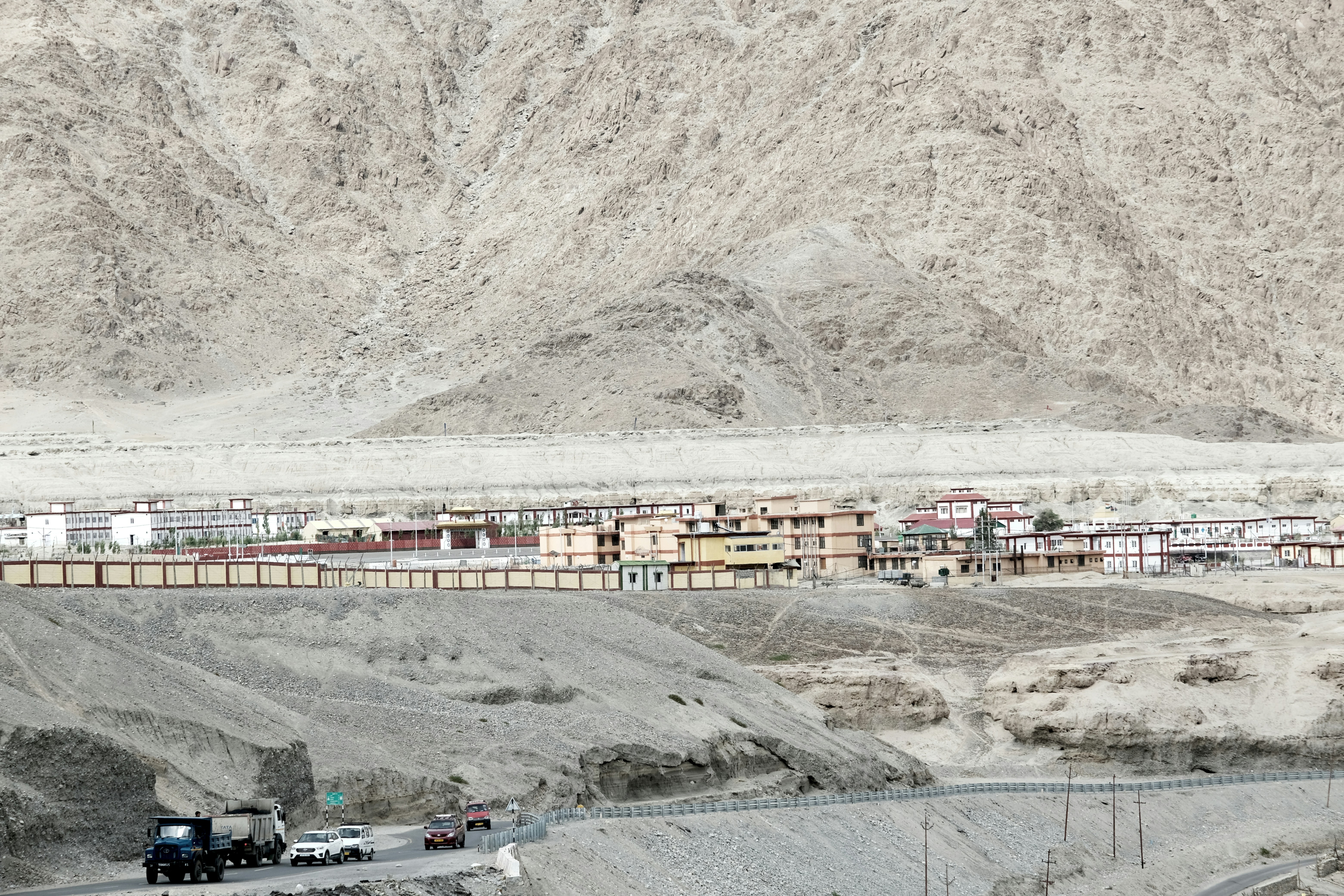 Cluster of buildings nestled in a vast, arid landscape with rugged mountains in the background.