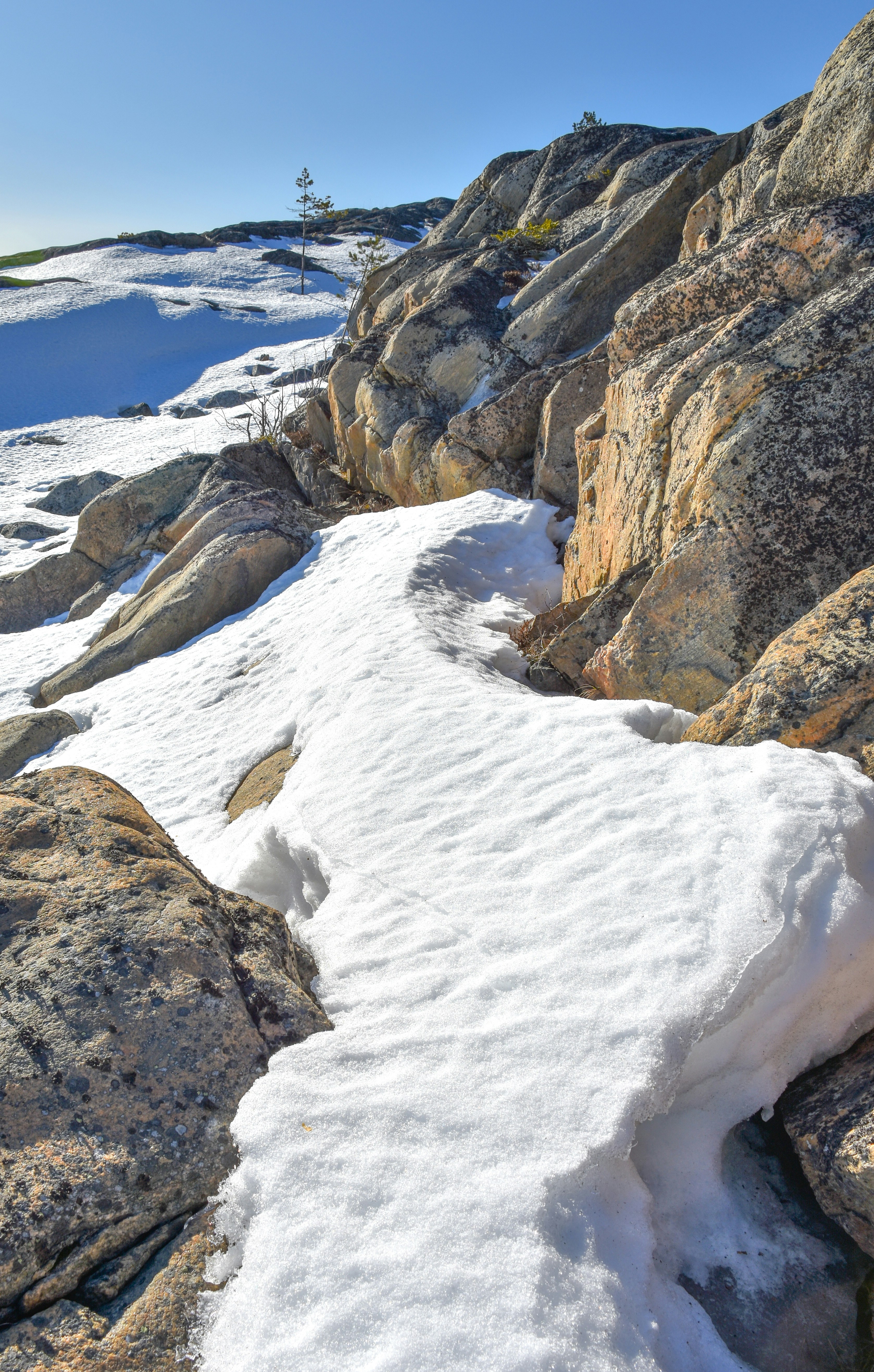 Snowy path winds through rocky landscape under blue sky. photo – Free ...