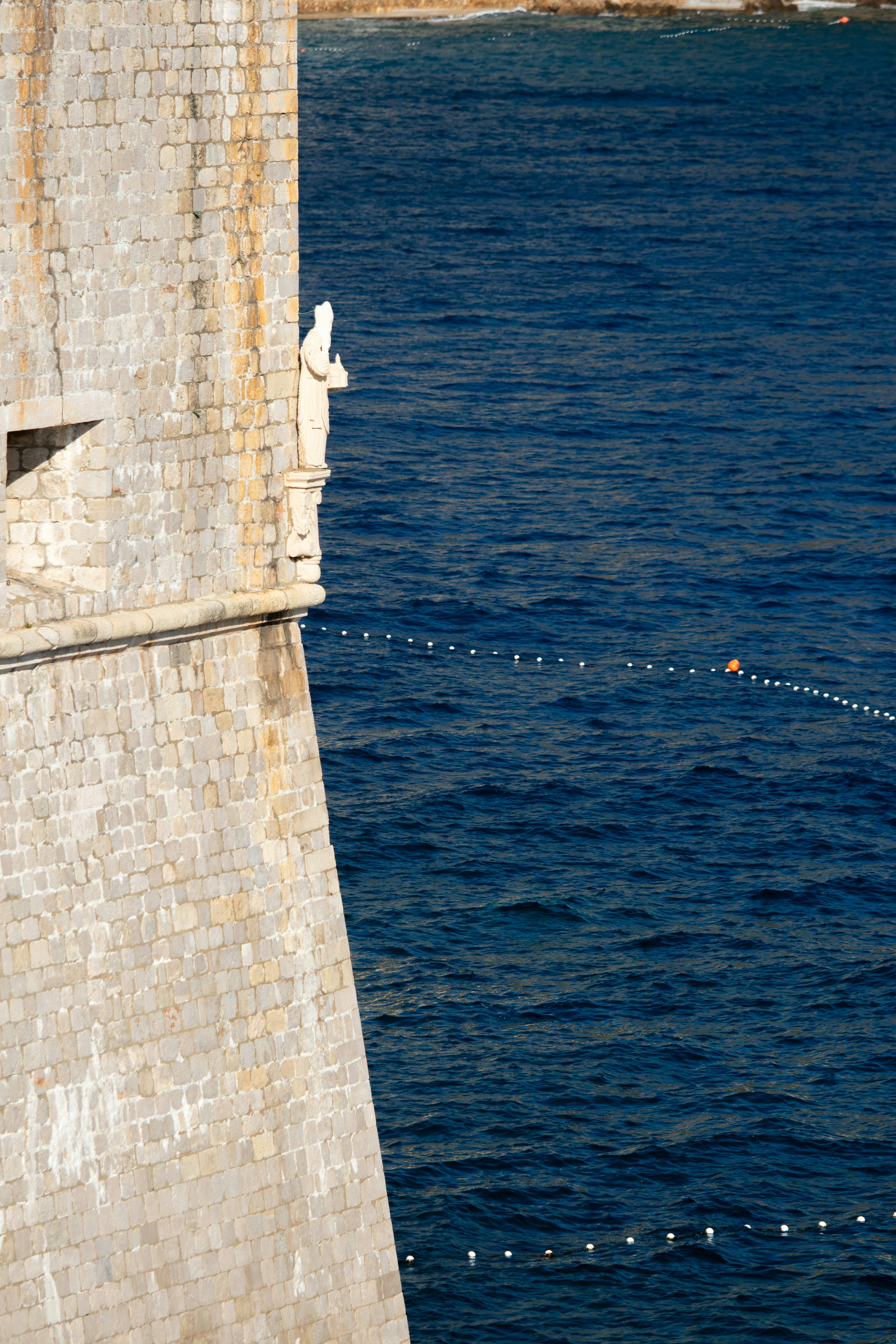 Stone Sentinel on the Fortress Wall Over a Cobalt Sea