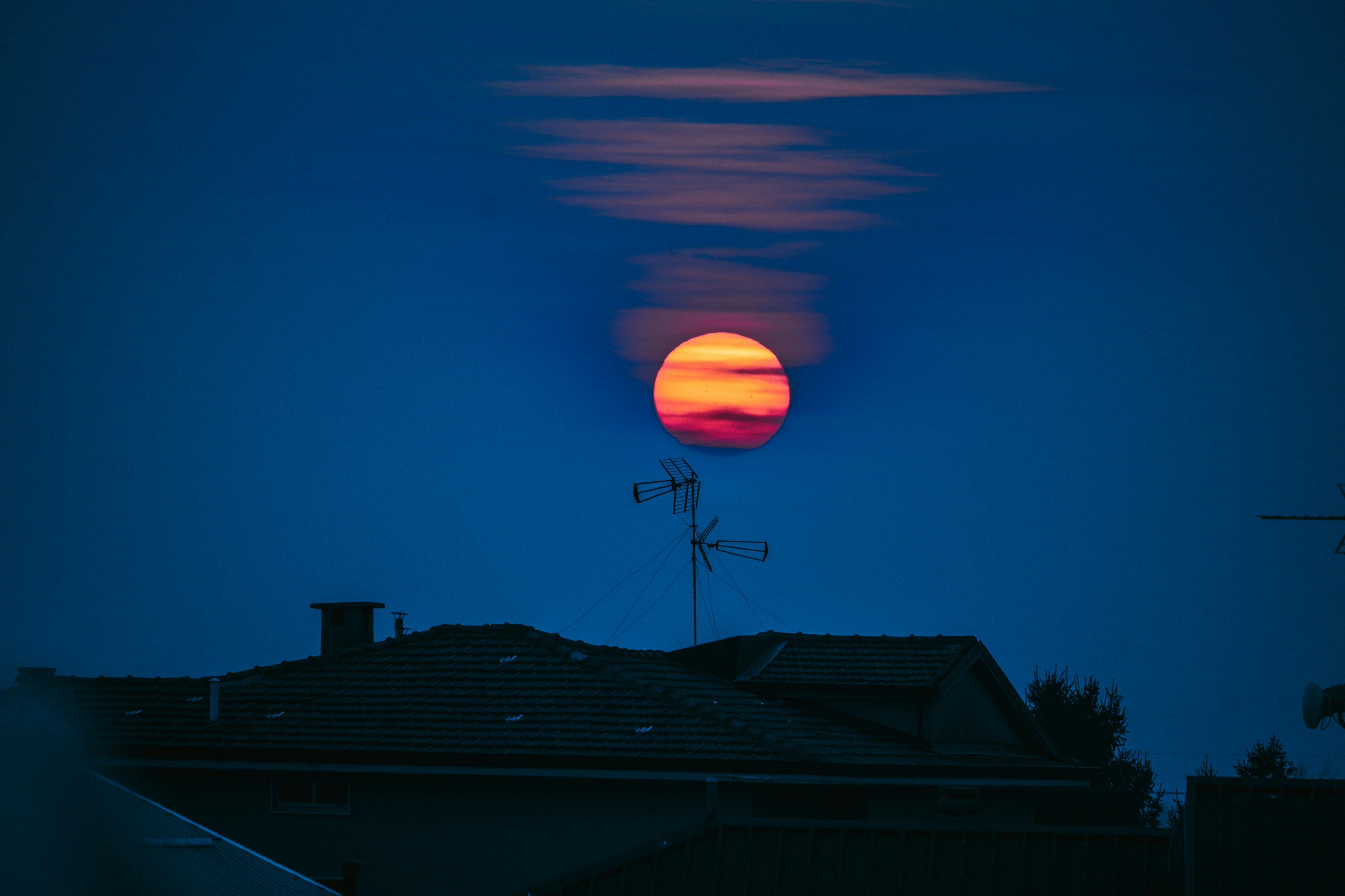 Vibrant sunset aligns with a rooftop antenna against a deep blue sky.