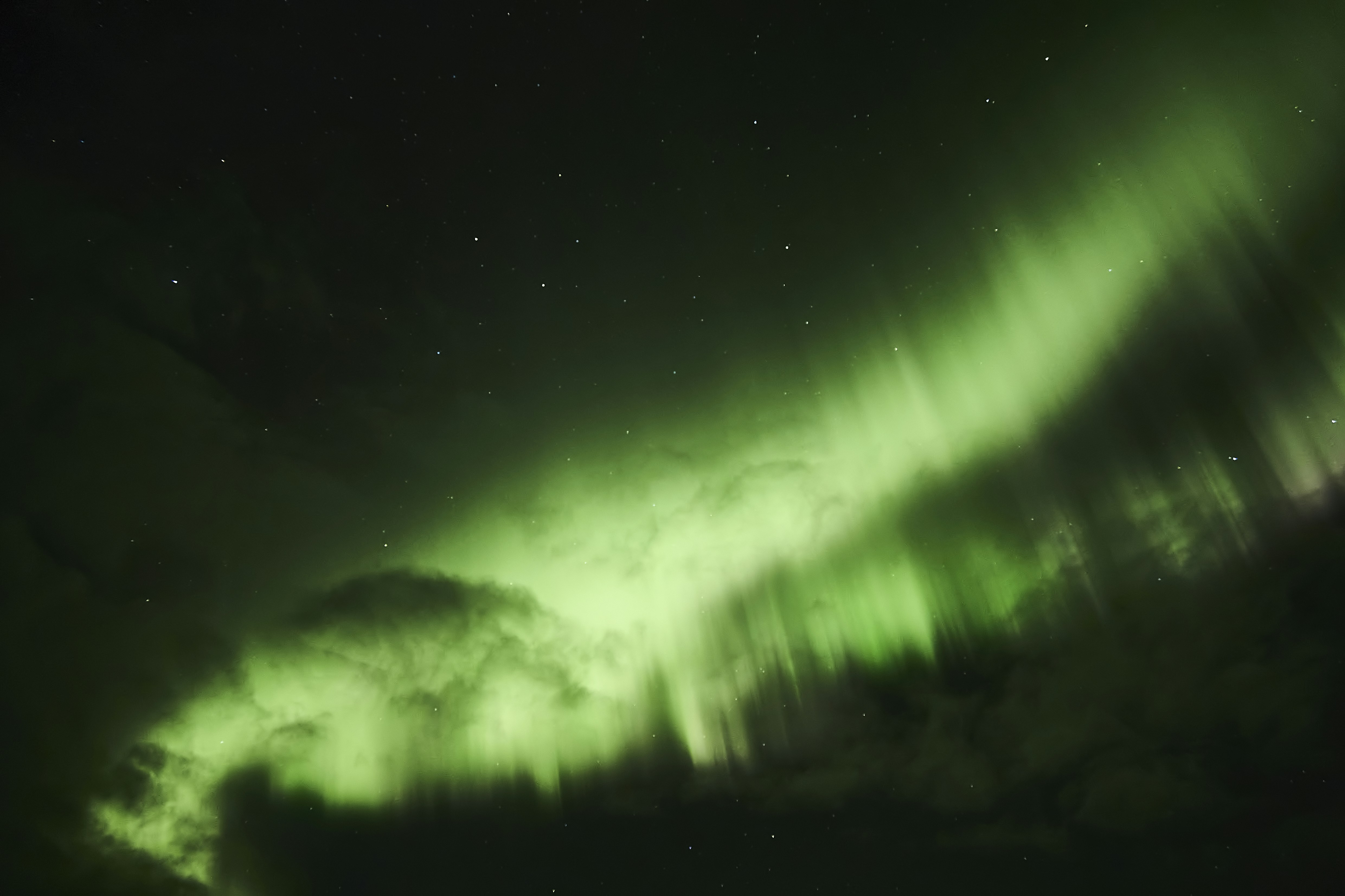 Vivid green aurora borealis swirling across a starry night sky.