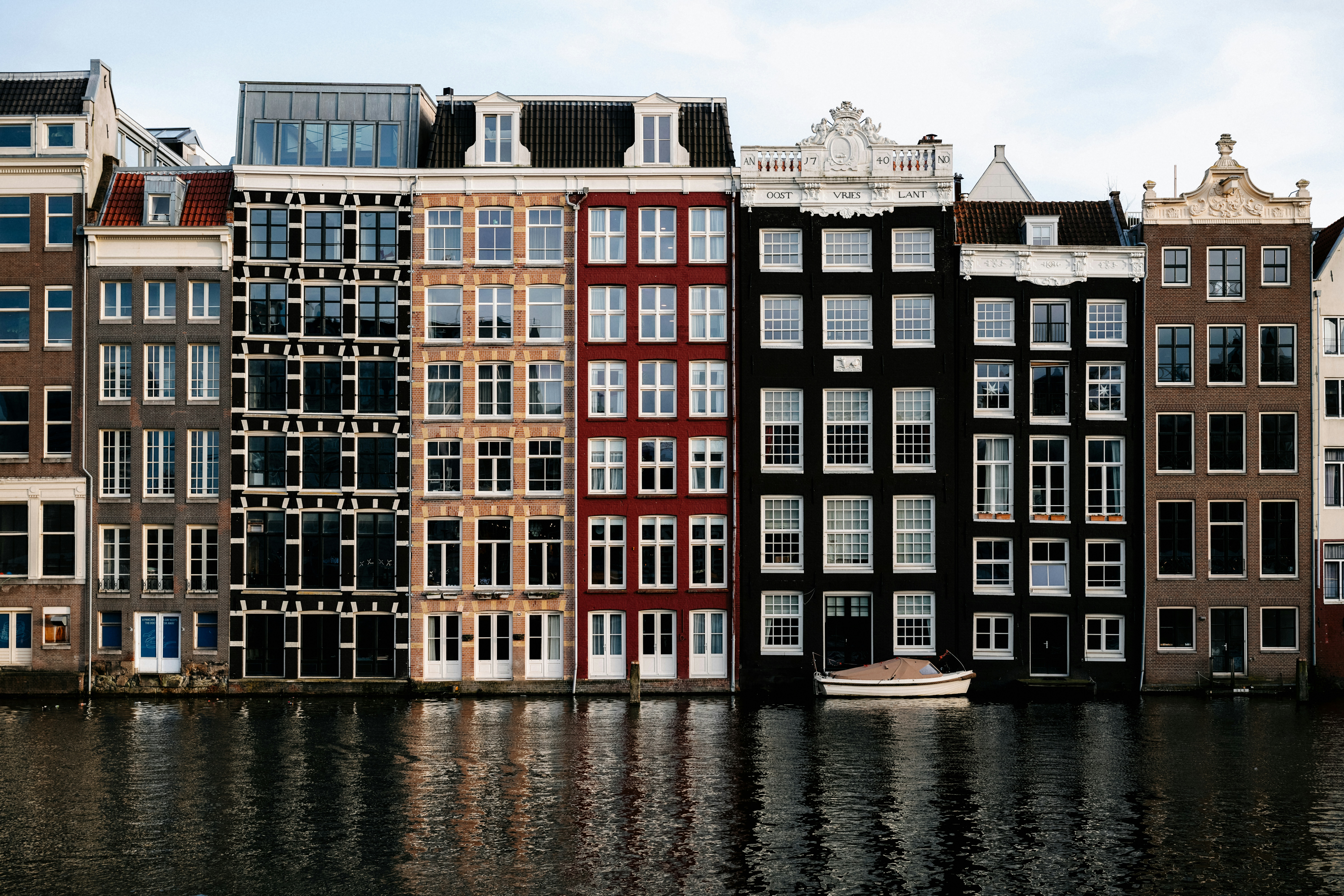 Colorful canal-side buildings with varied architectural styles reflecting in the water.