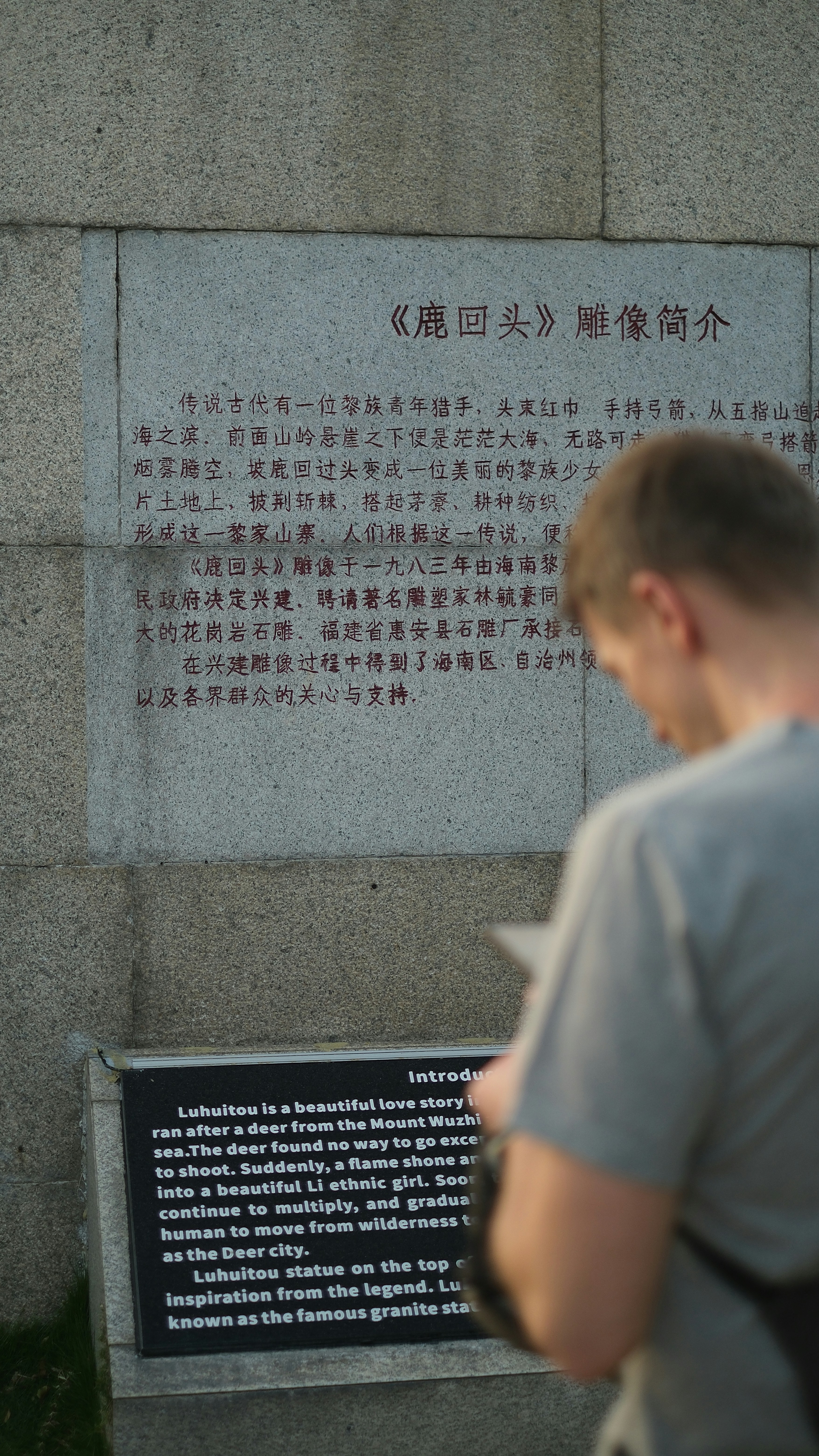 Man reads the plaque detailing the "deer turning back" statue. photo ...