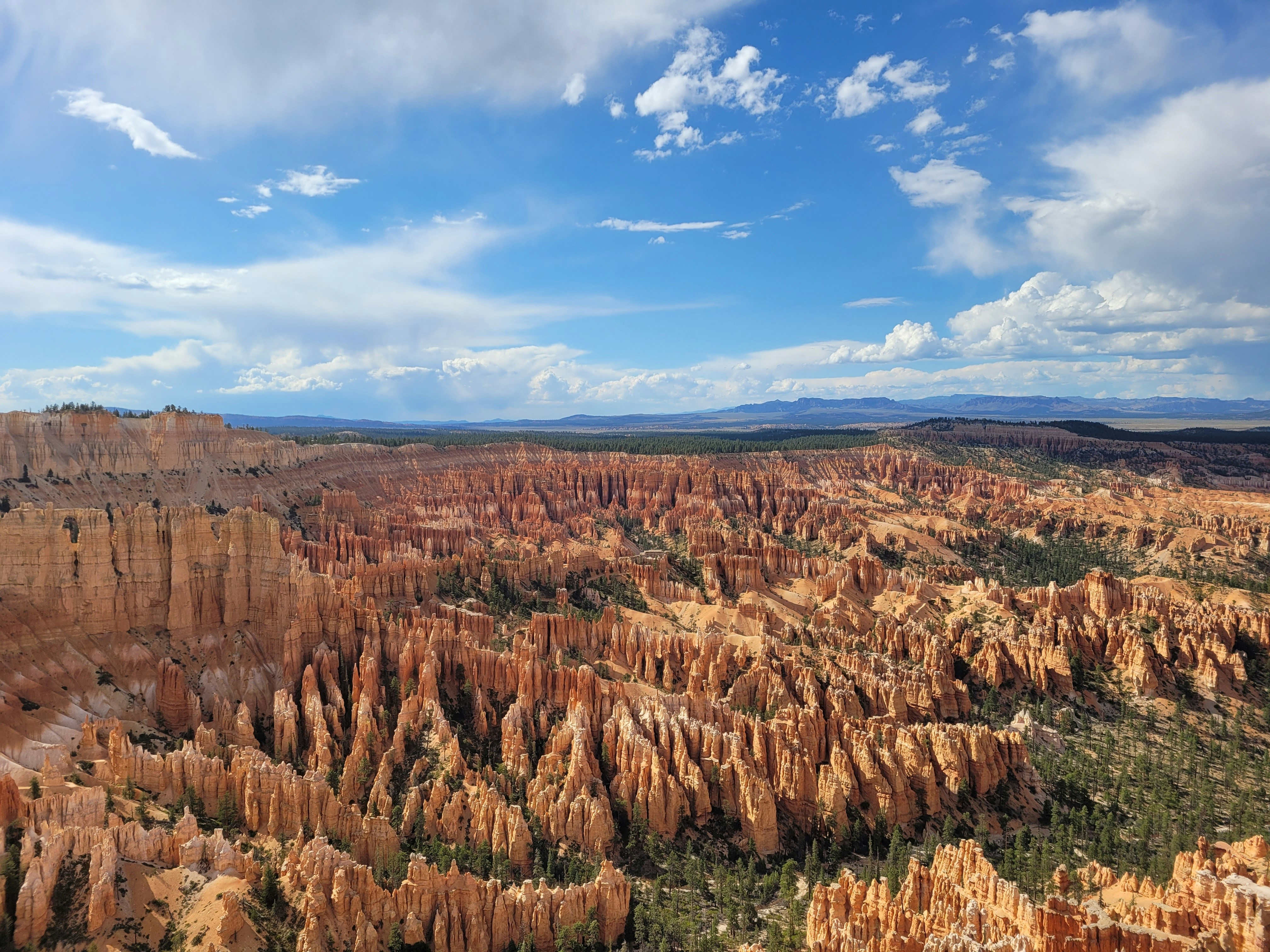 Expansive view of Bryce Canyon's unique hoodoo formations under a vibrant blue sky with scattered clouds.