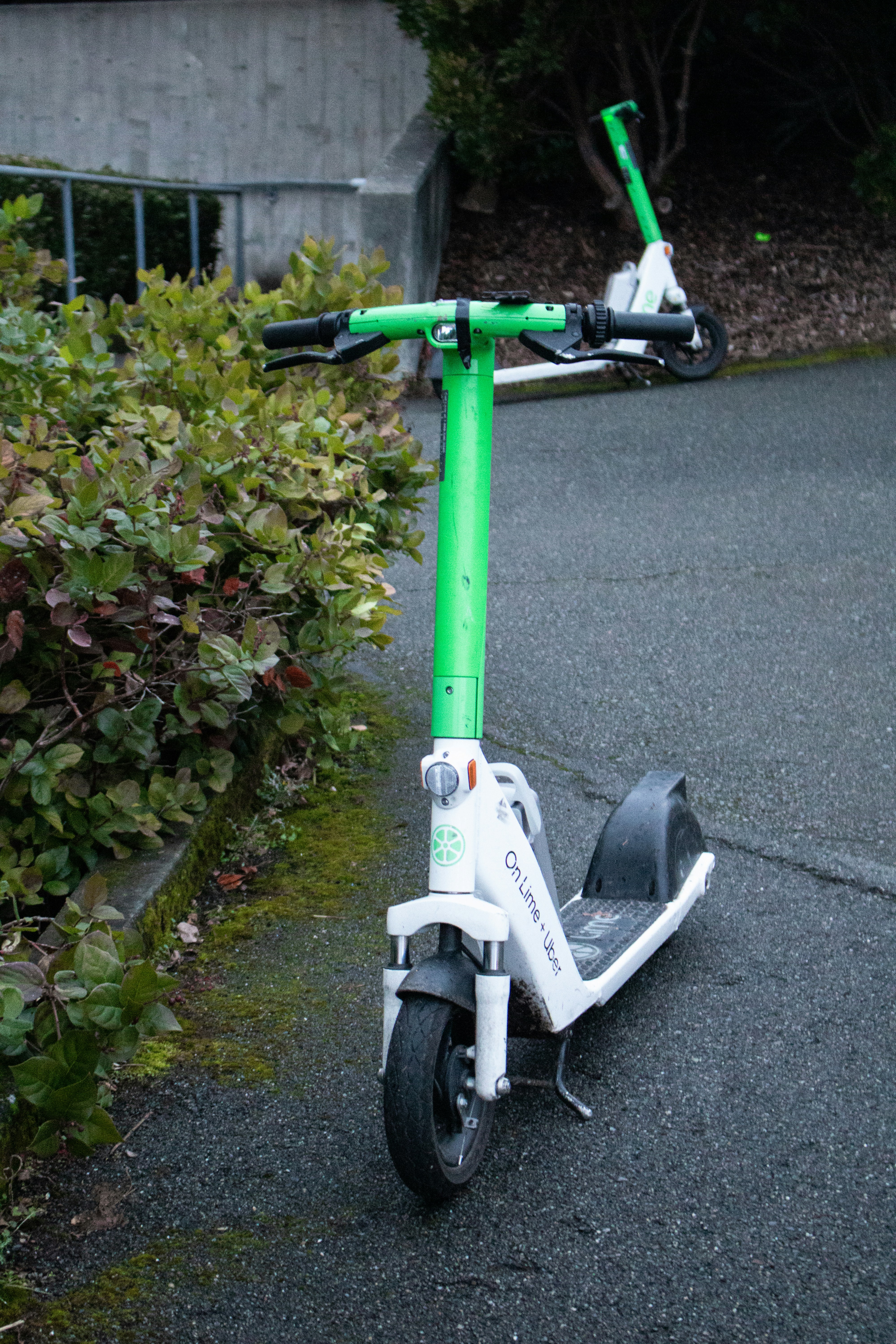 A parked lime bike | A lime scooter sits on a paved path.