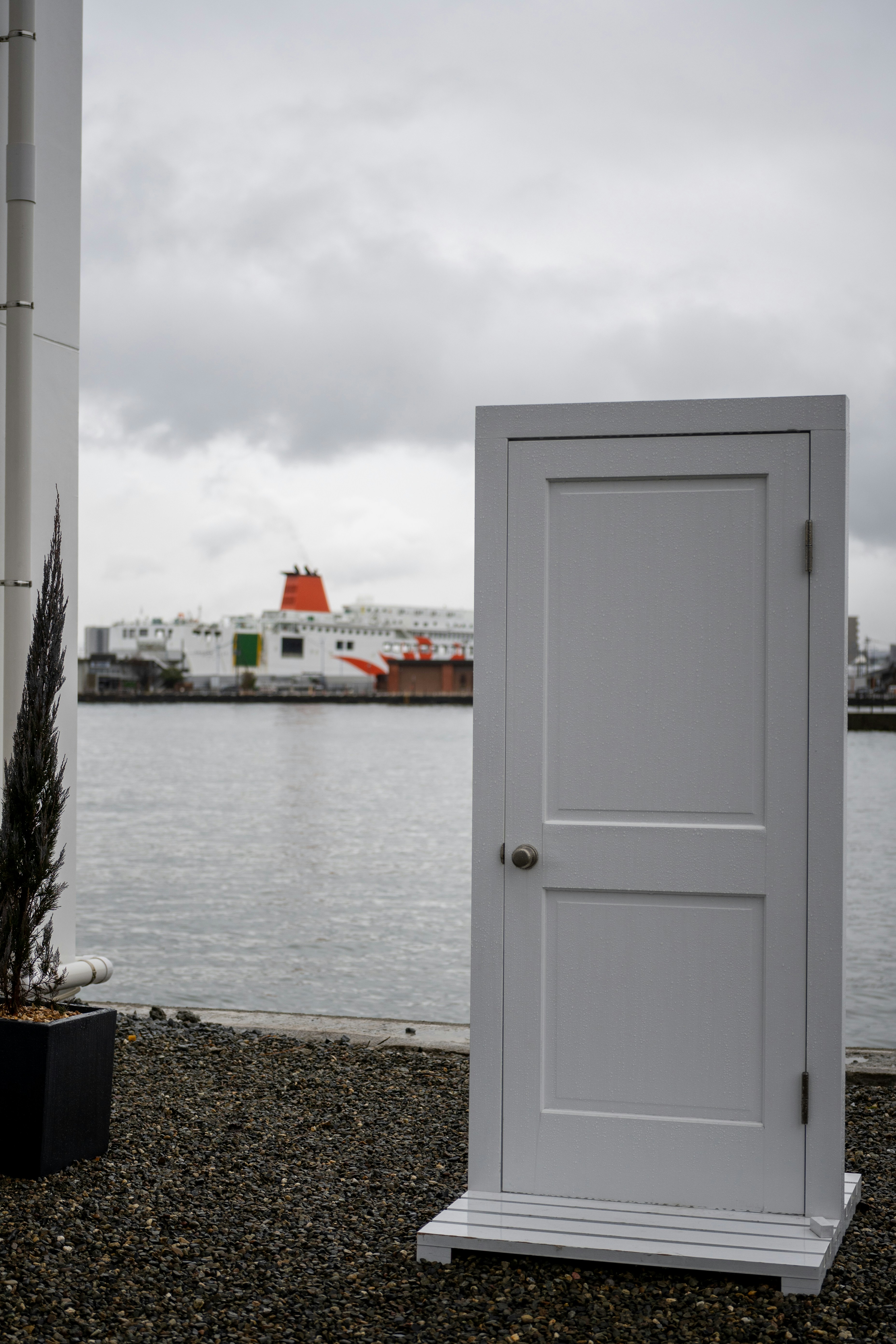 White door stands next to water with boat.