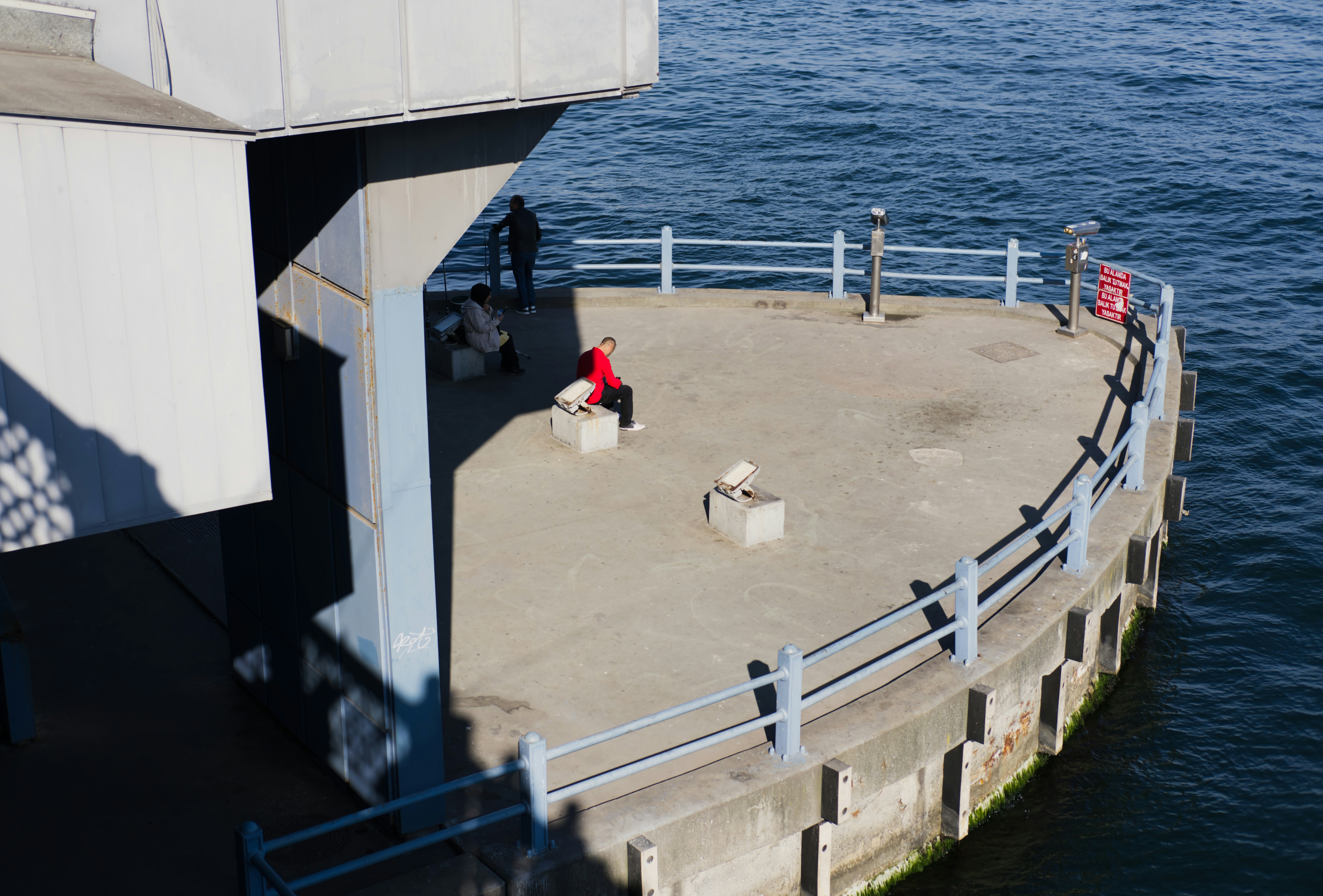Red-Clad Figure at the Harbor Curve: A Quiet Moment Over Blue Water