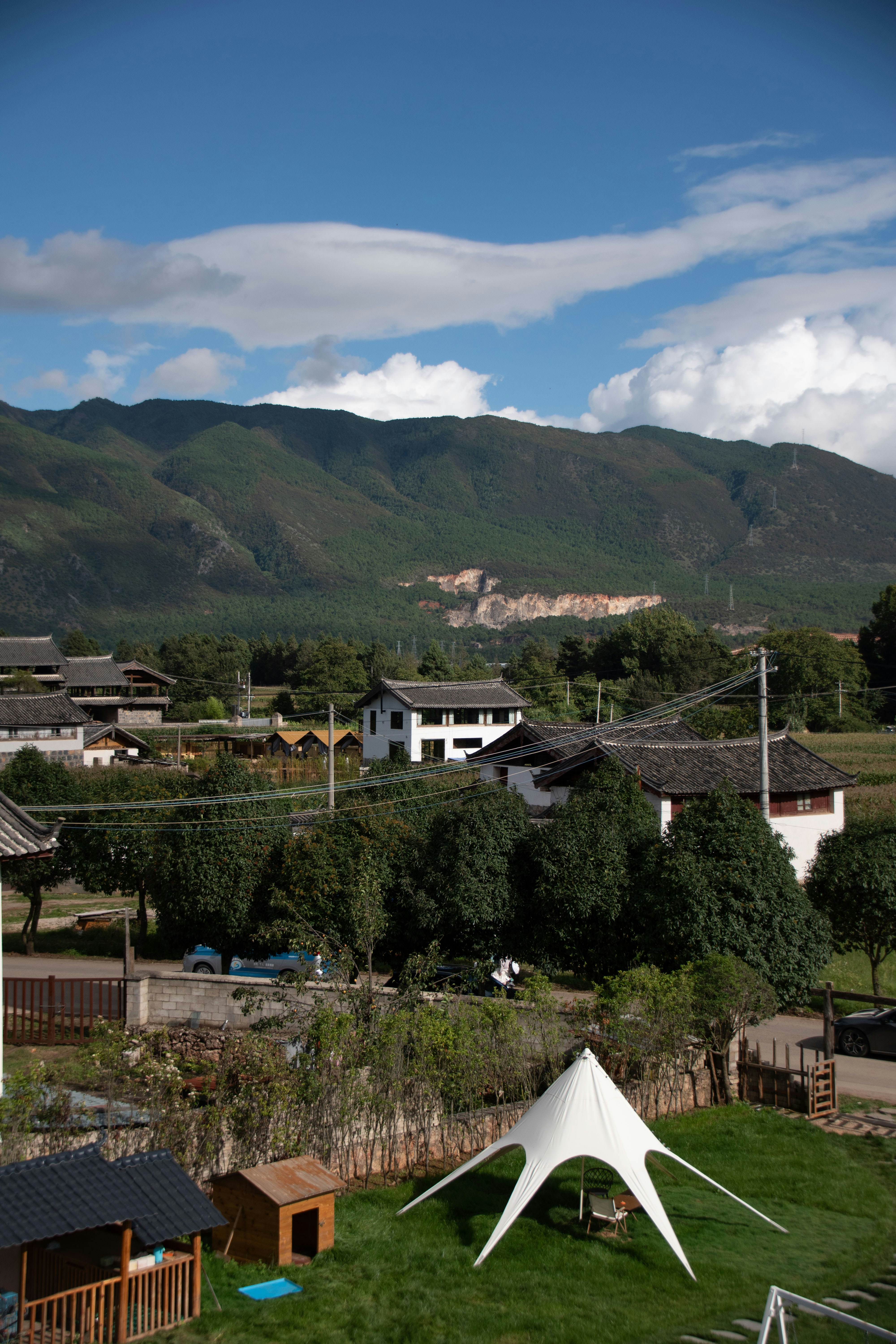 White Canopy Over a Tranquil Valley Village Beneath Wide Blue Skies